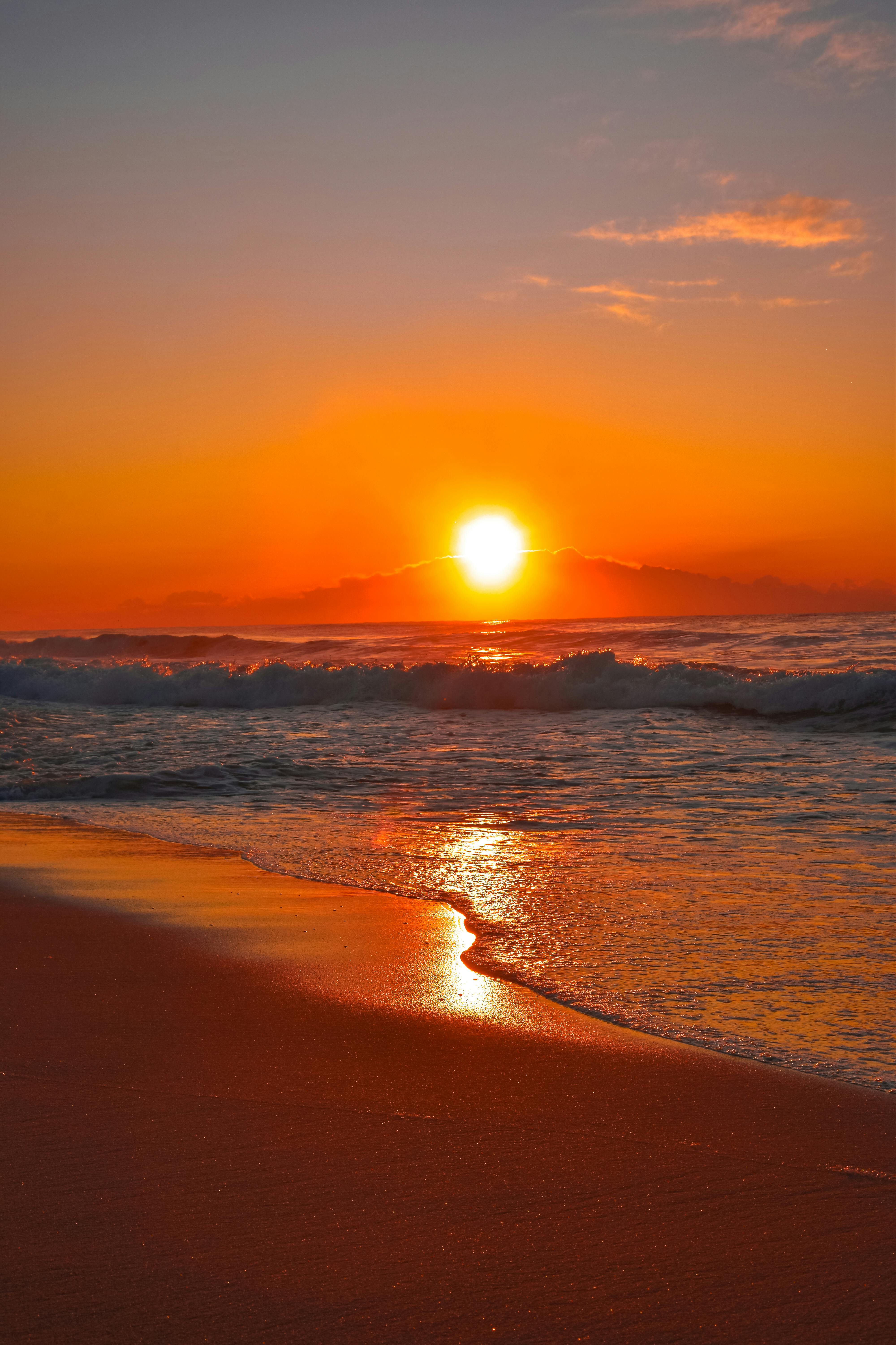 A sunset on the beach with waves and sand · Free Stock Photo
