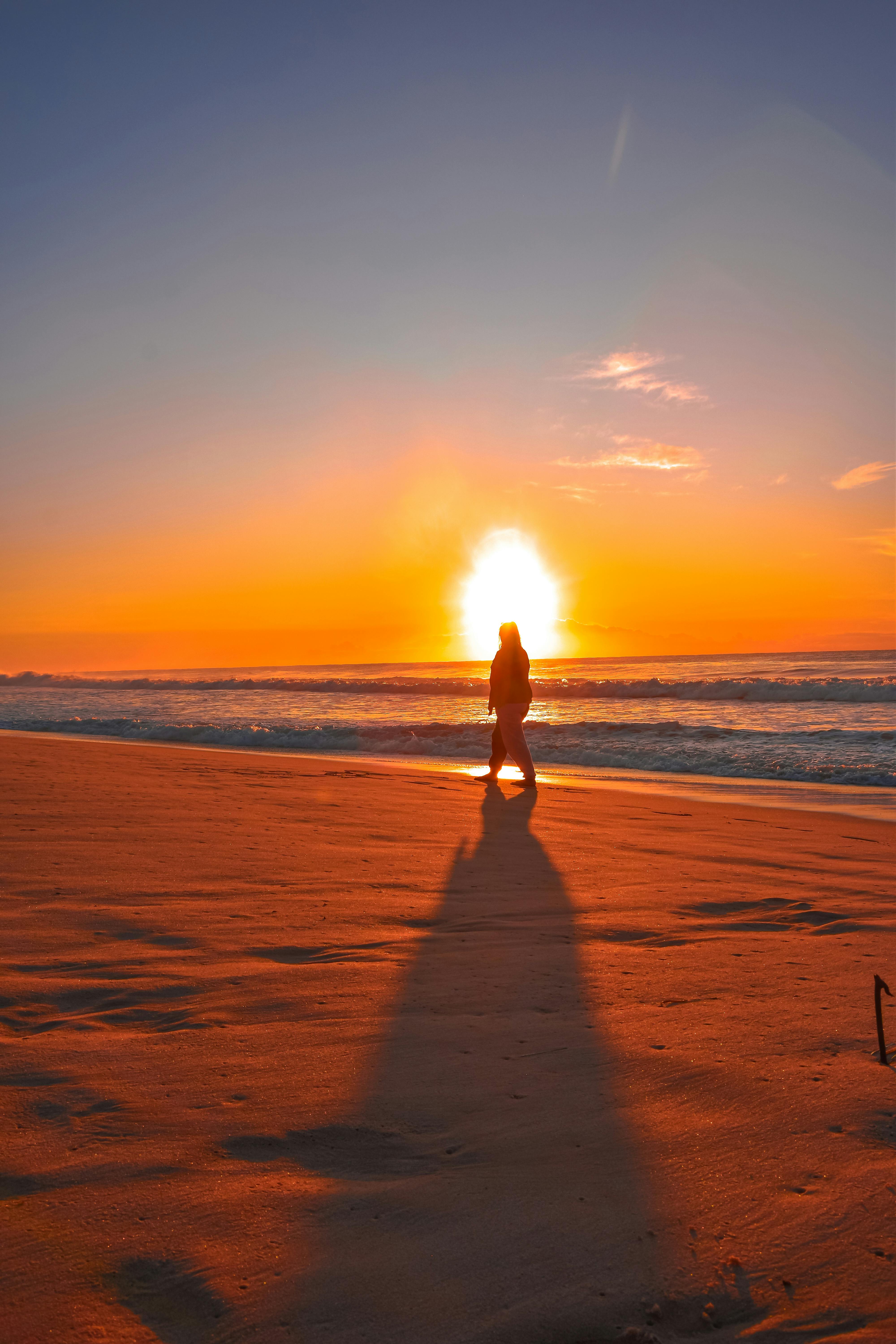 A person walking on the beach at sunset · Free Stock Photo