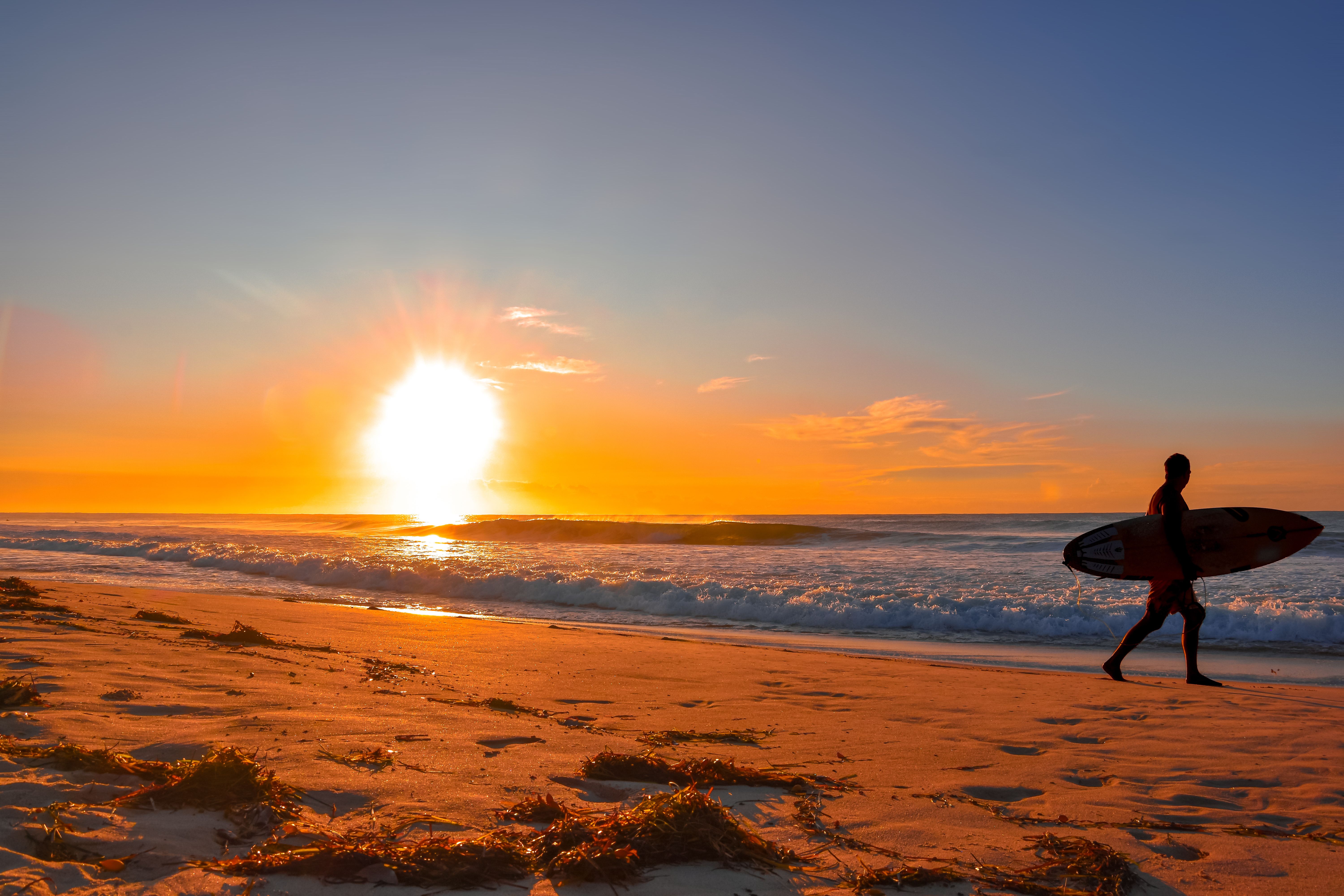 A person walking on the beach with a surfboard · Free Stock Photo