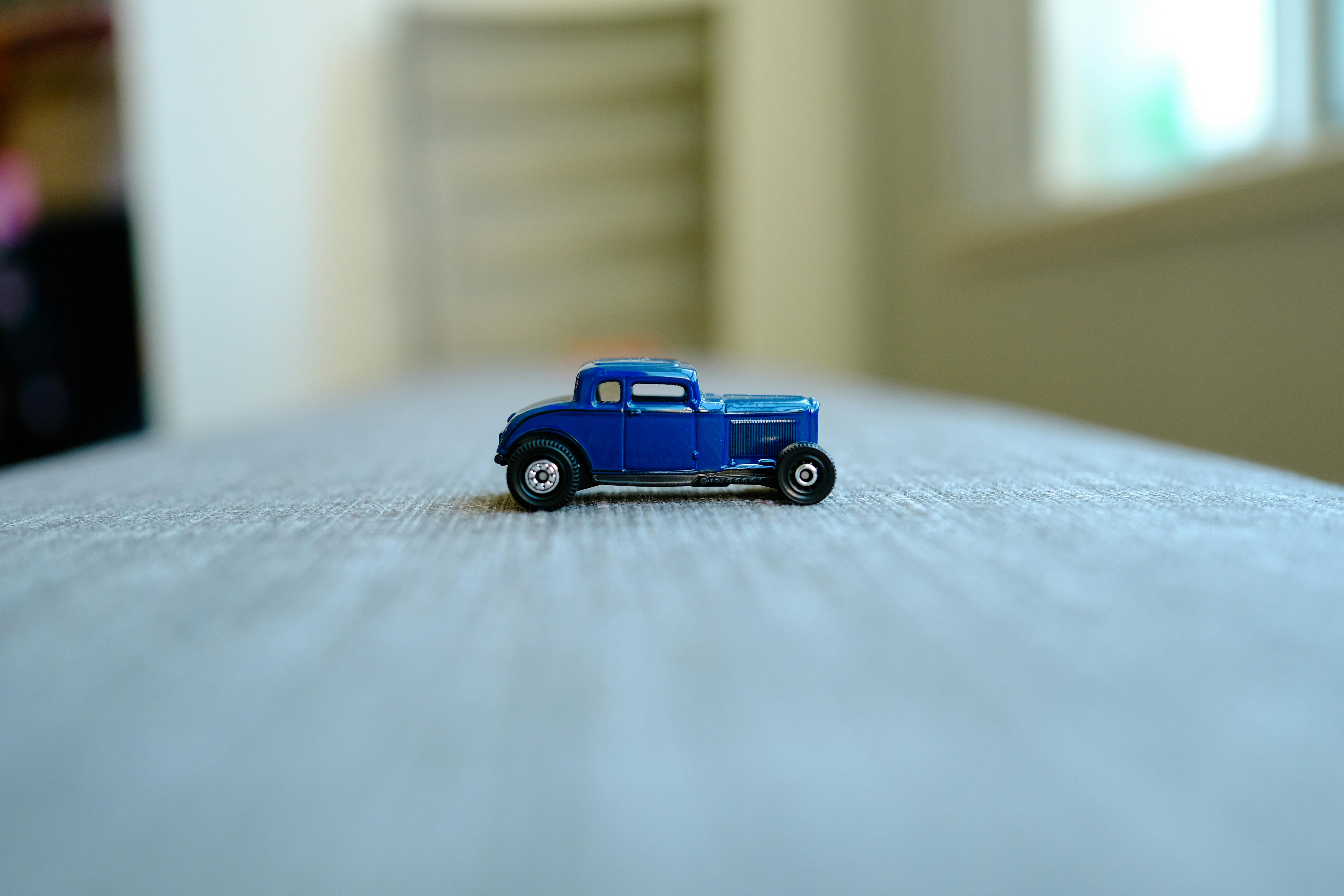 A toy blue car on a table · Free Stock Photo