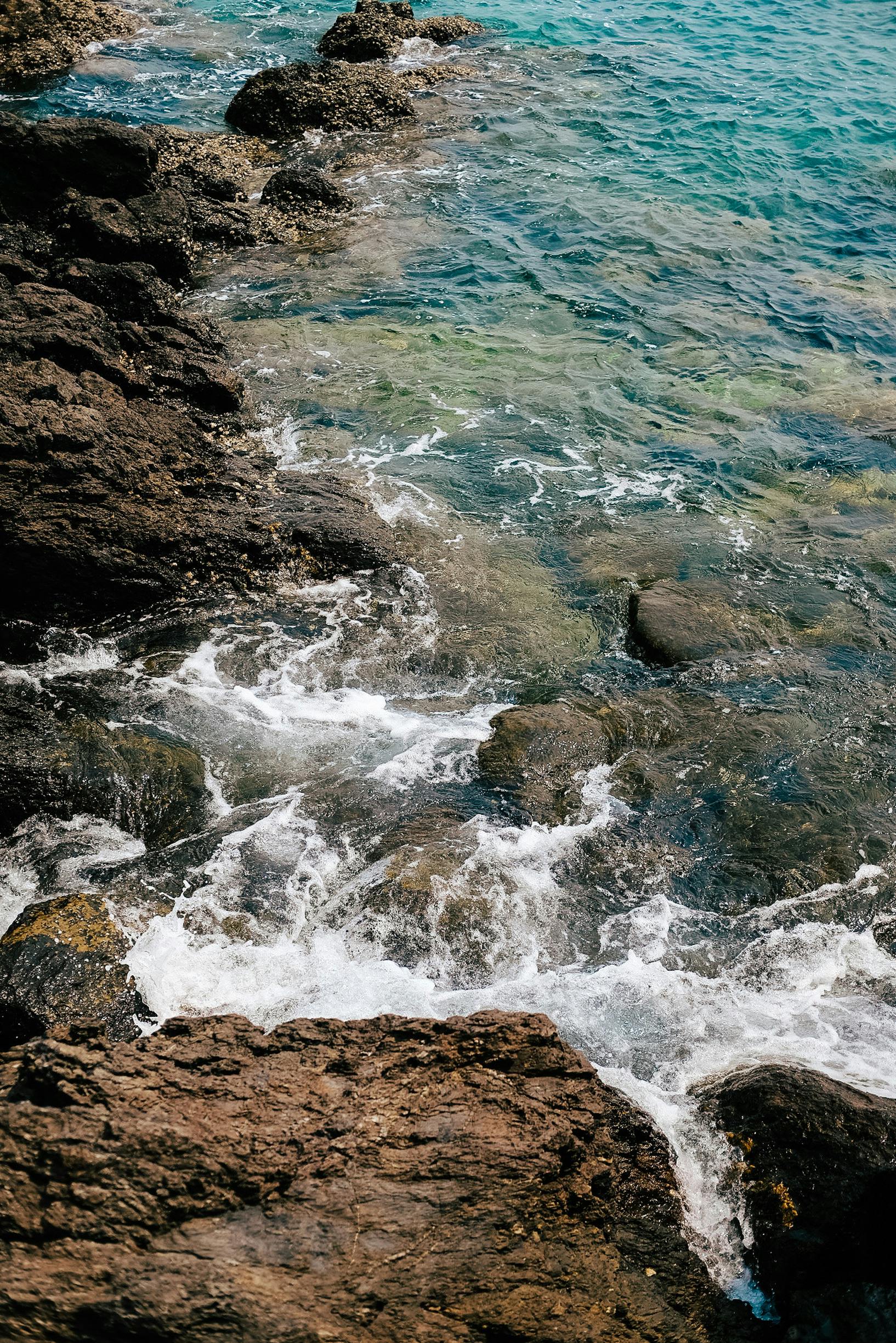 A rocky shoreline with waves crashing into the rocks · Free Stock Photo