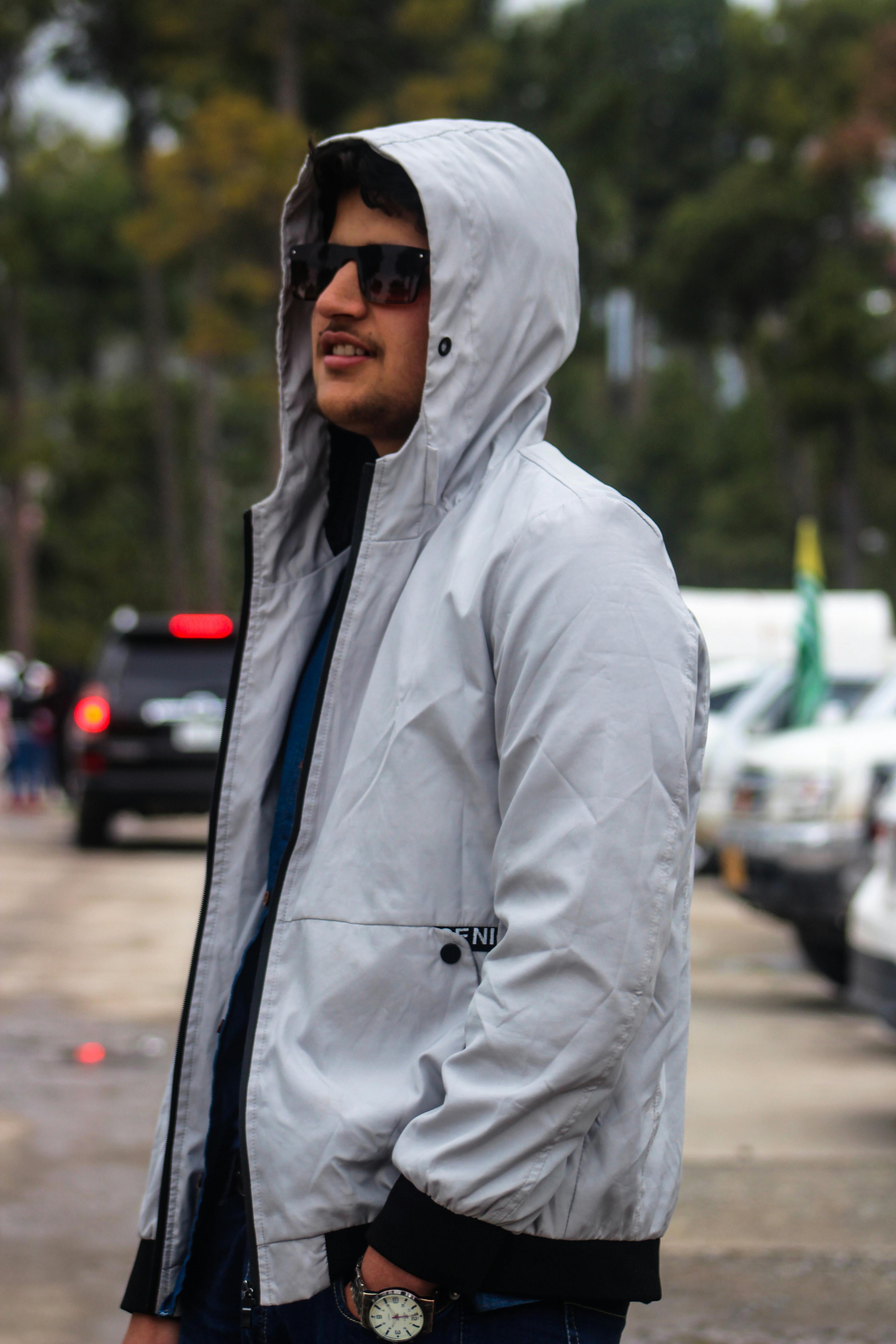 Young Man in a Grey Hooded Jacket and Sunglasses Standing in a Parking ...
