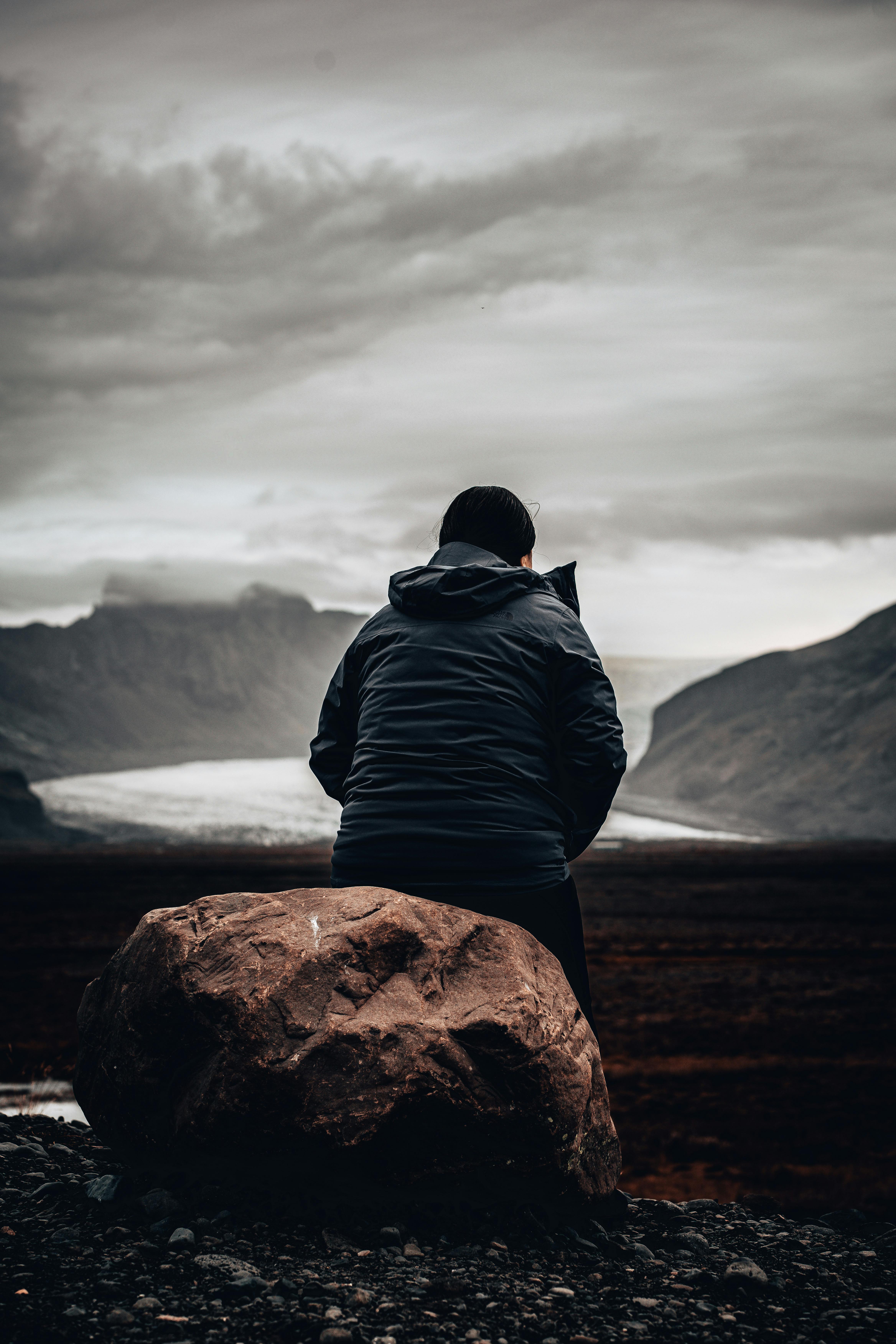 Overcast over Man Sitting on Rock · Free Stock Photo