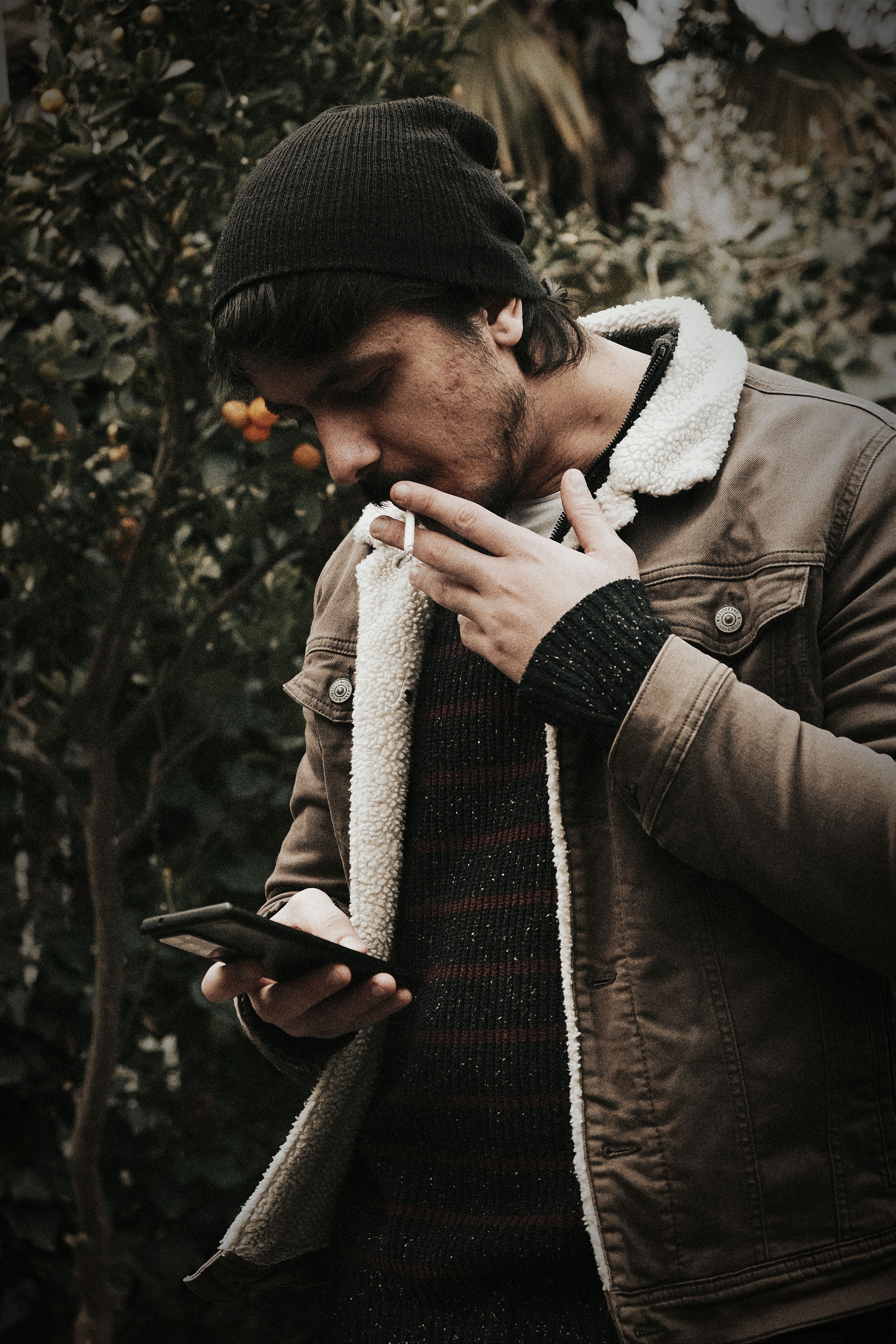 Man Smoking and Looking at Smartphone · Free Stock Photo
