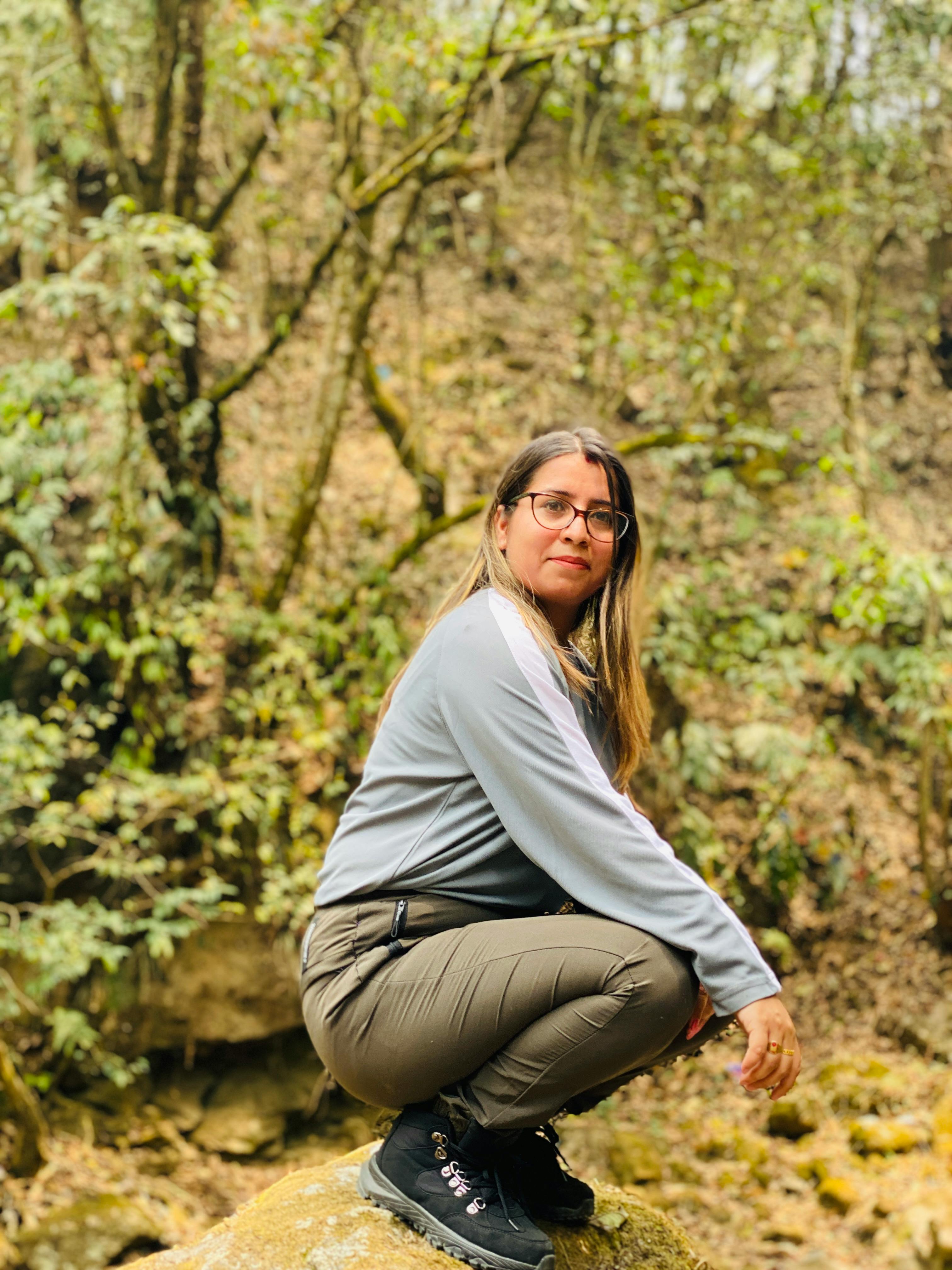 Young Woman Crouching on a Rock in the Forest · Free Stock Photo