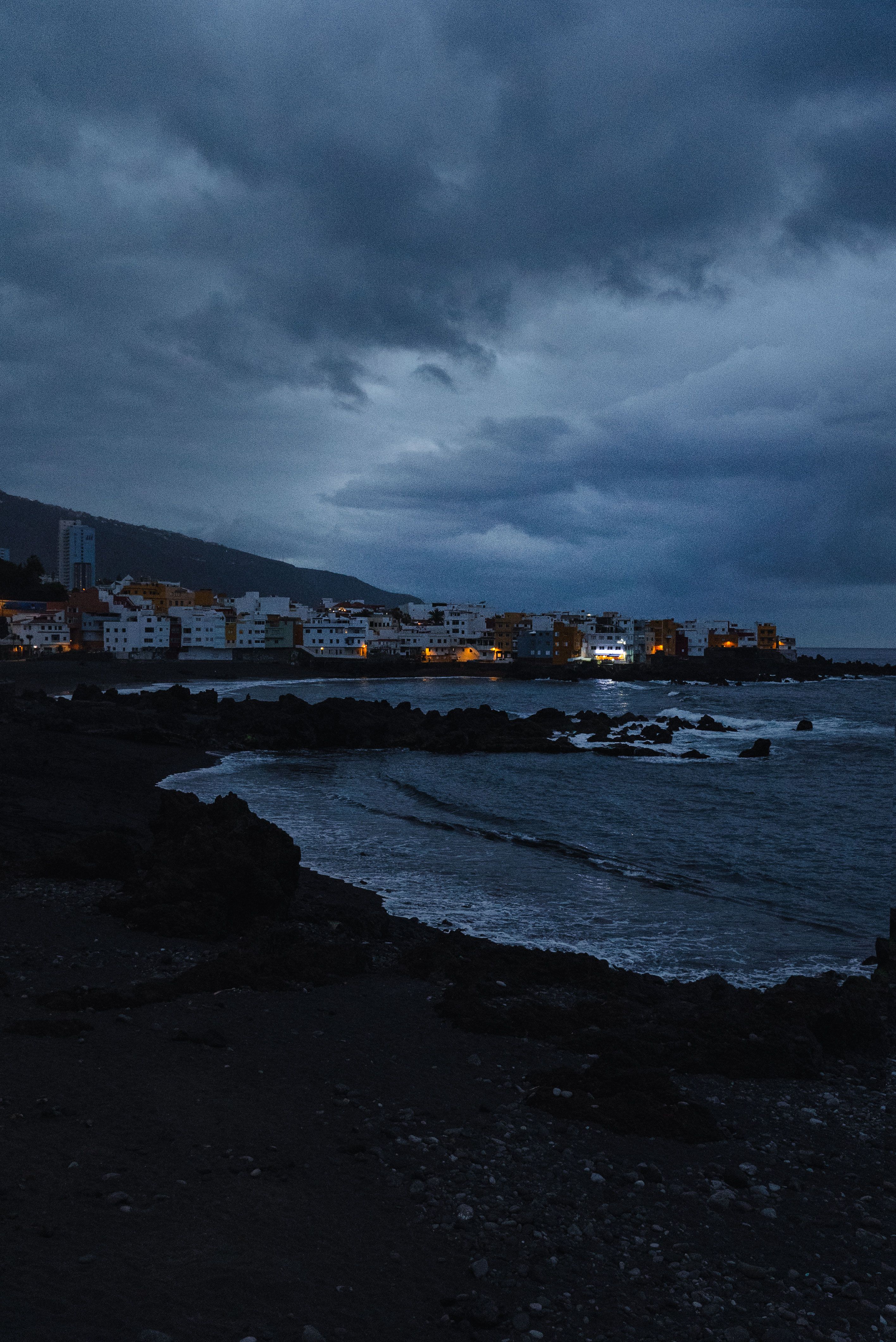 Rain Clouds over Sea Shore with Town behind · Free Stock Photo
