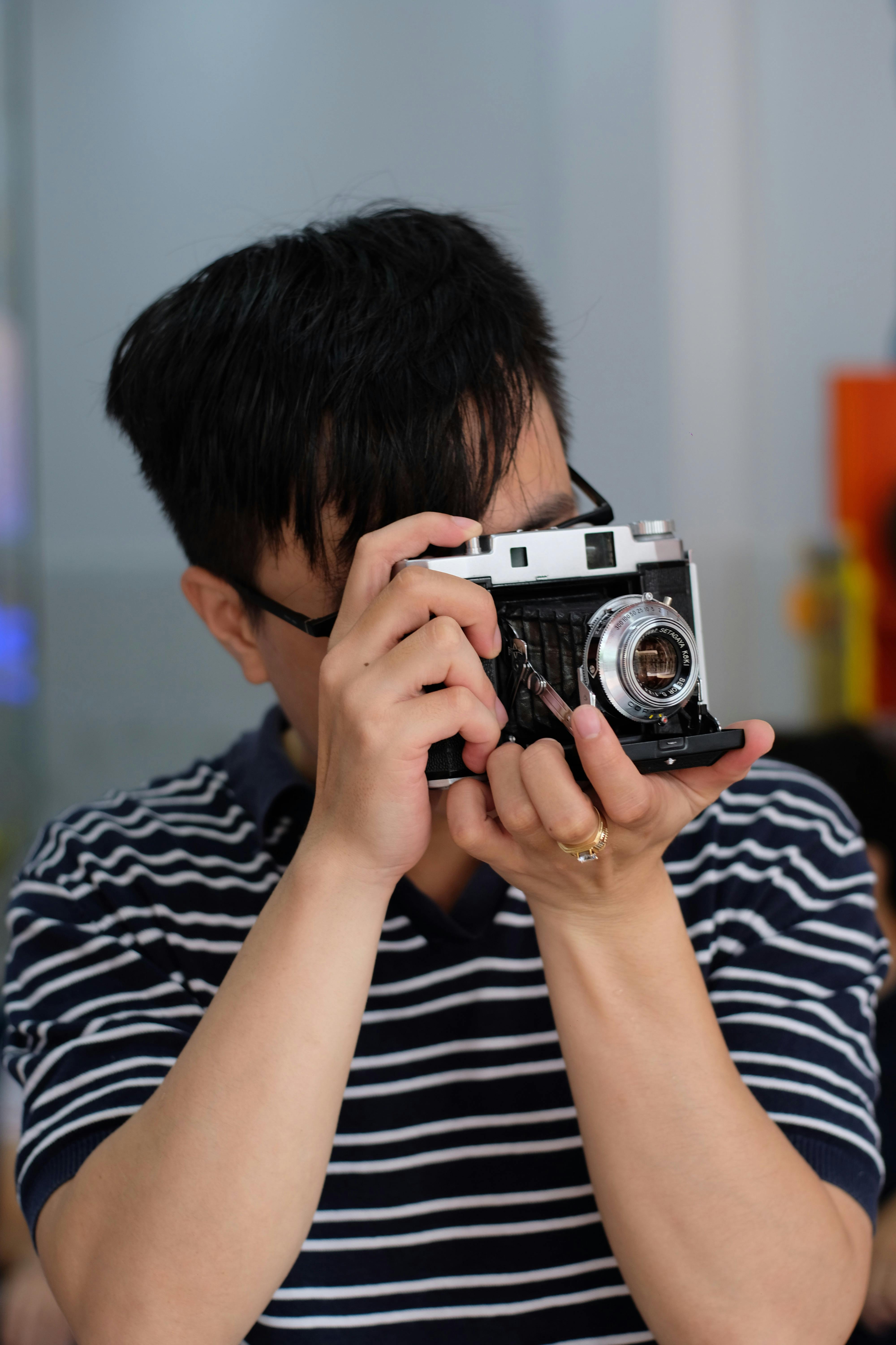 A man holding an old camera in his hand · Free Stock Photo