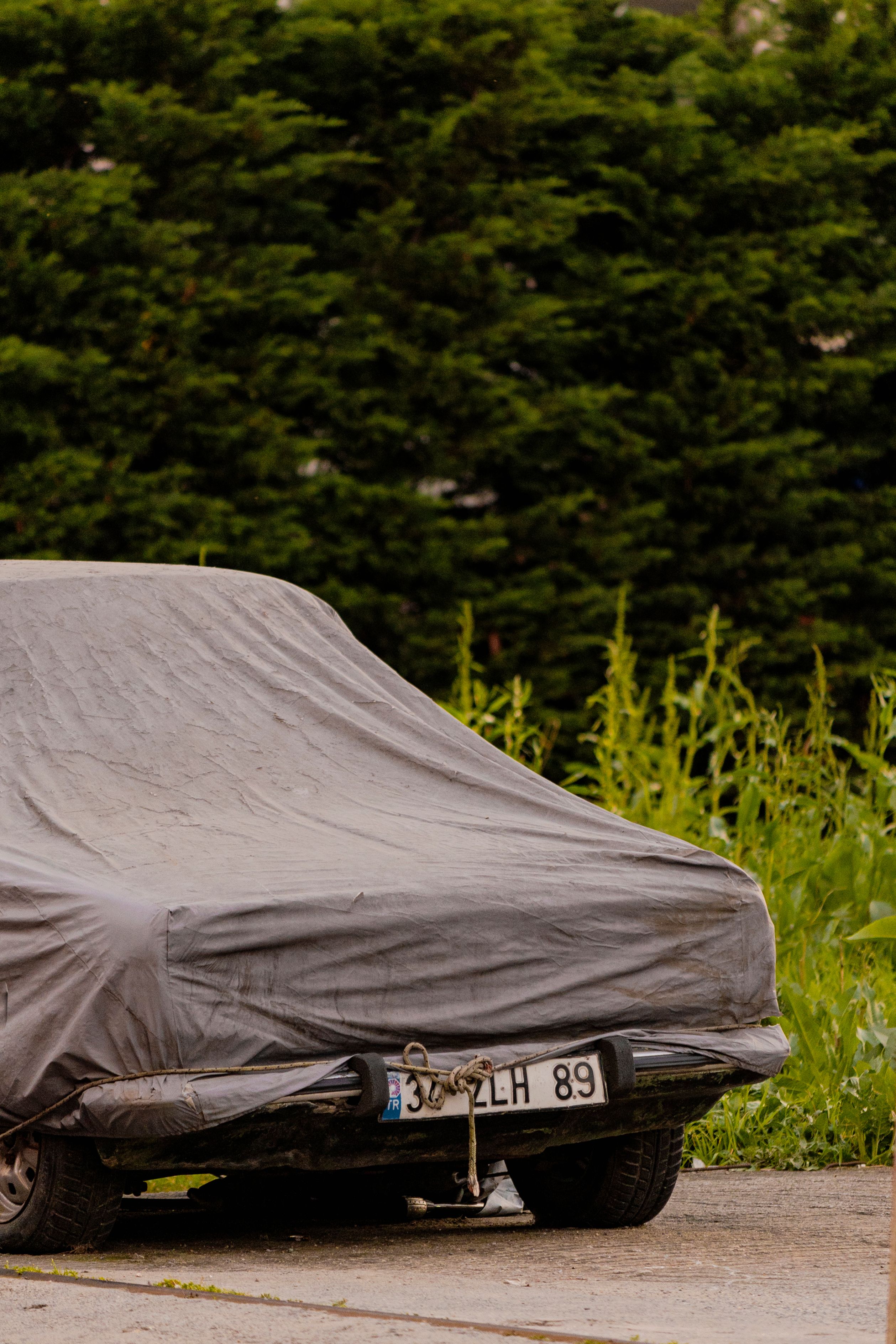 A car covered in a tarp on the side of the road · Free Stock Photo