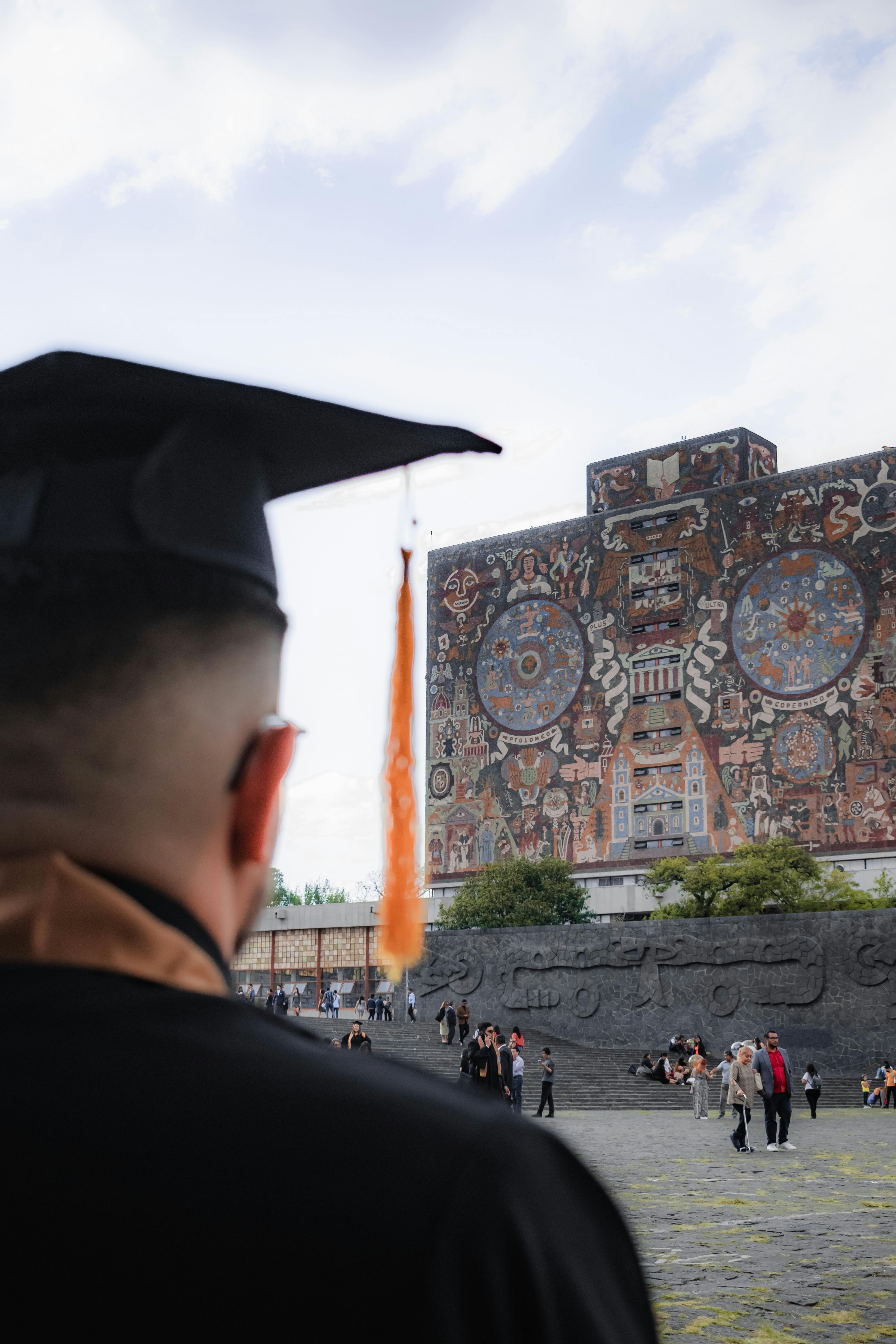Man Wearing a Graduation Gown and Standing in front of the University ...