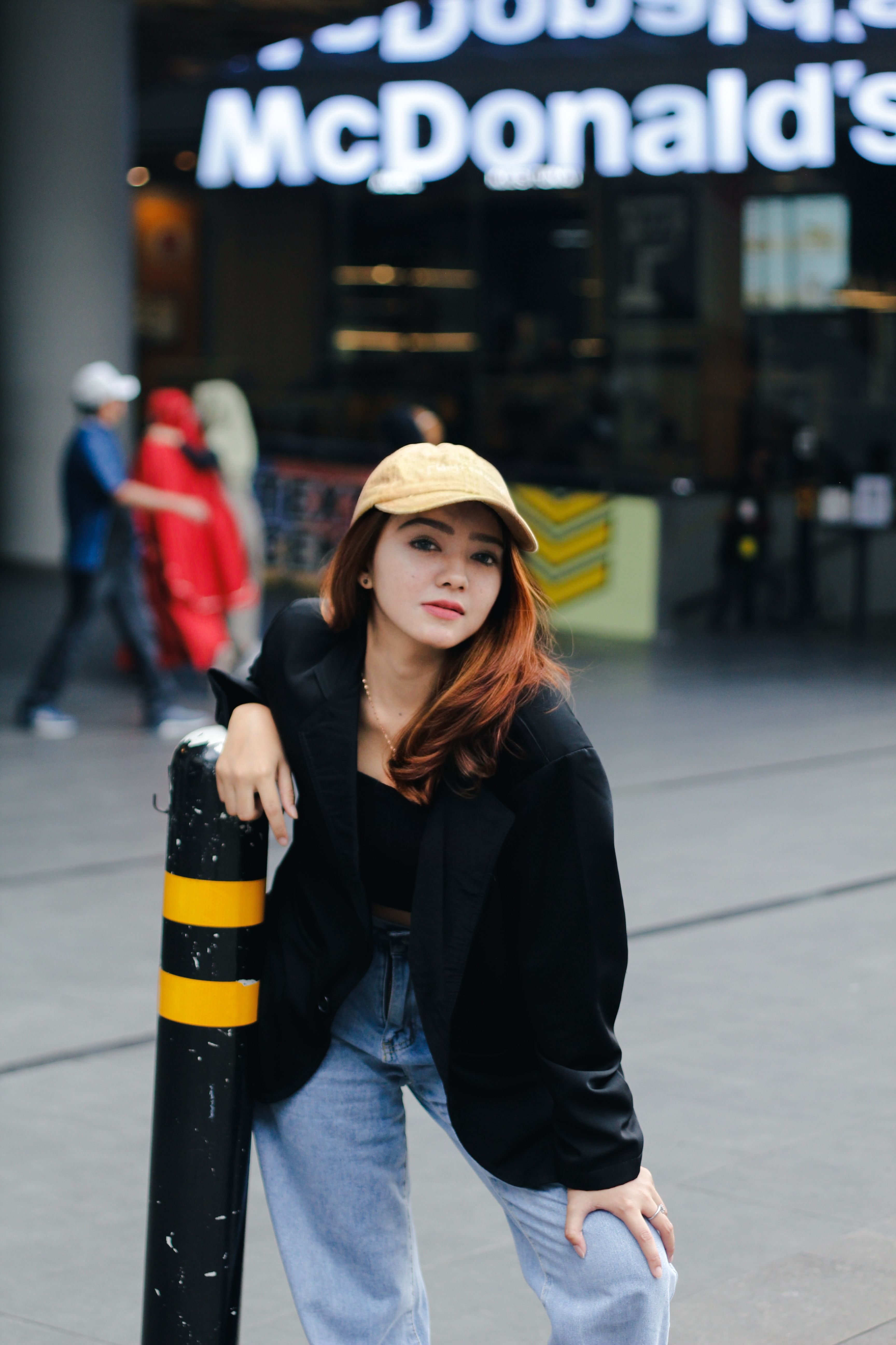 Young Woman in Cap Posing on Sidewalk by Post · Free Stock Photo