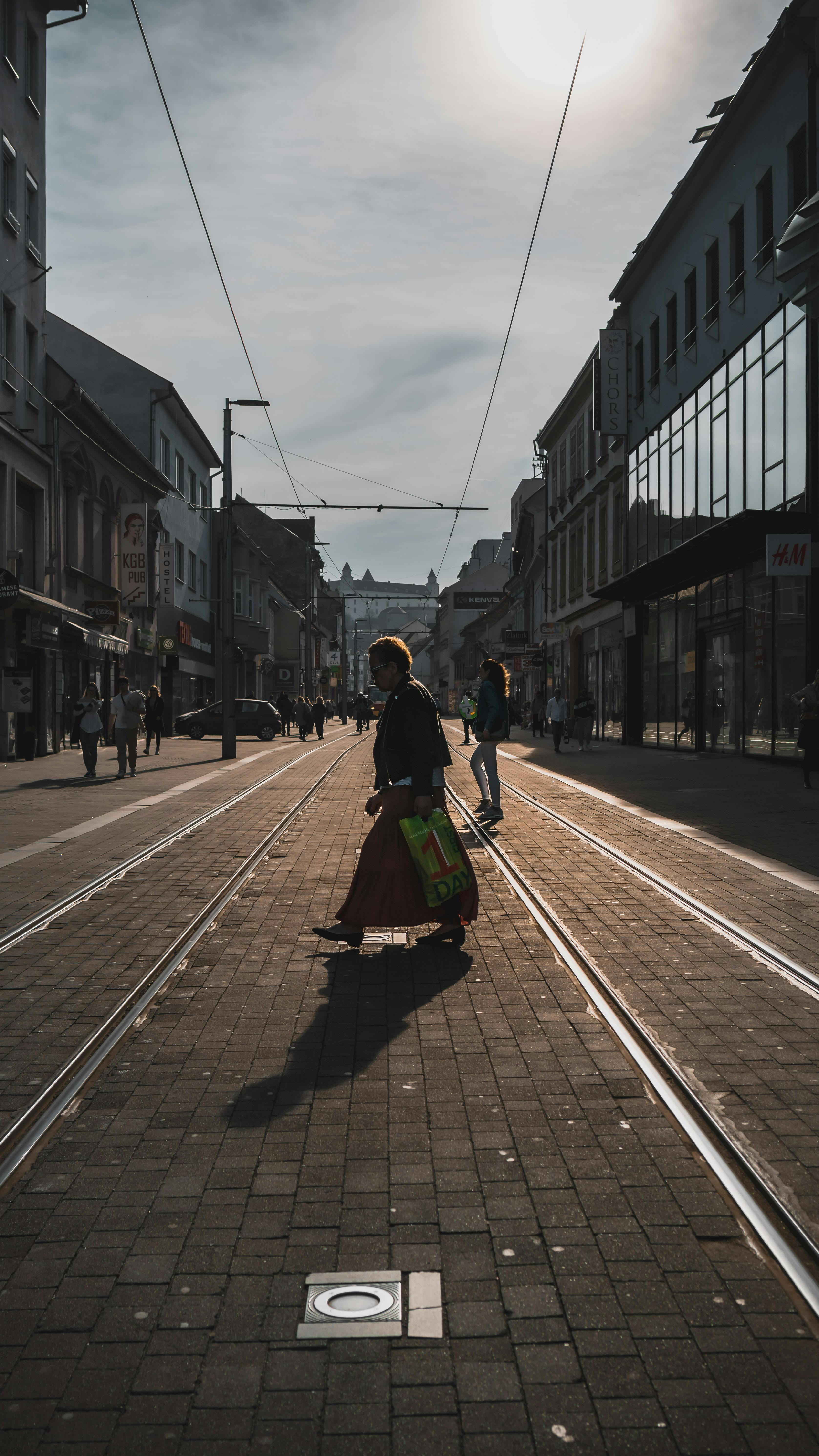 Woman Crossing a Paved Road with Tram Tracks · Free Stock Photo