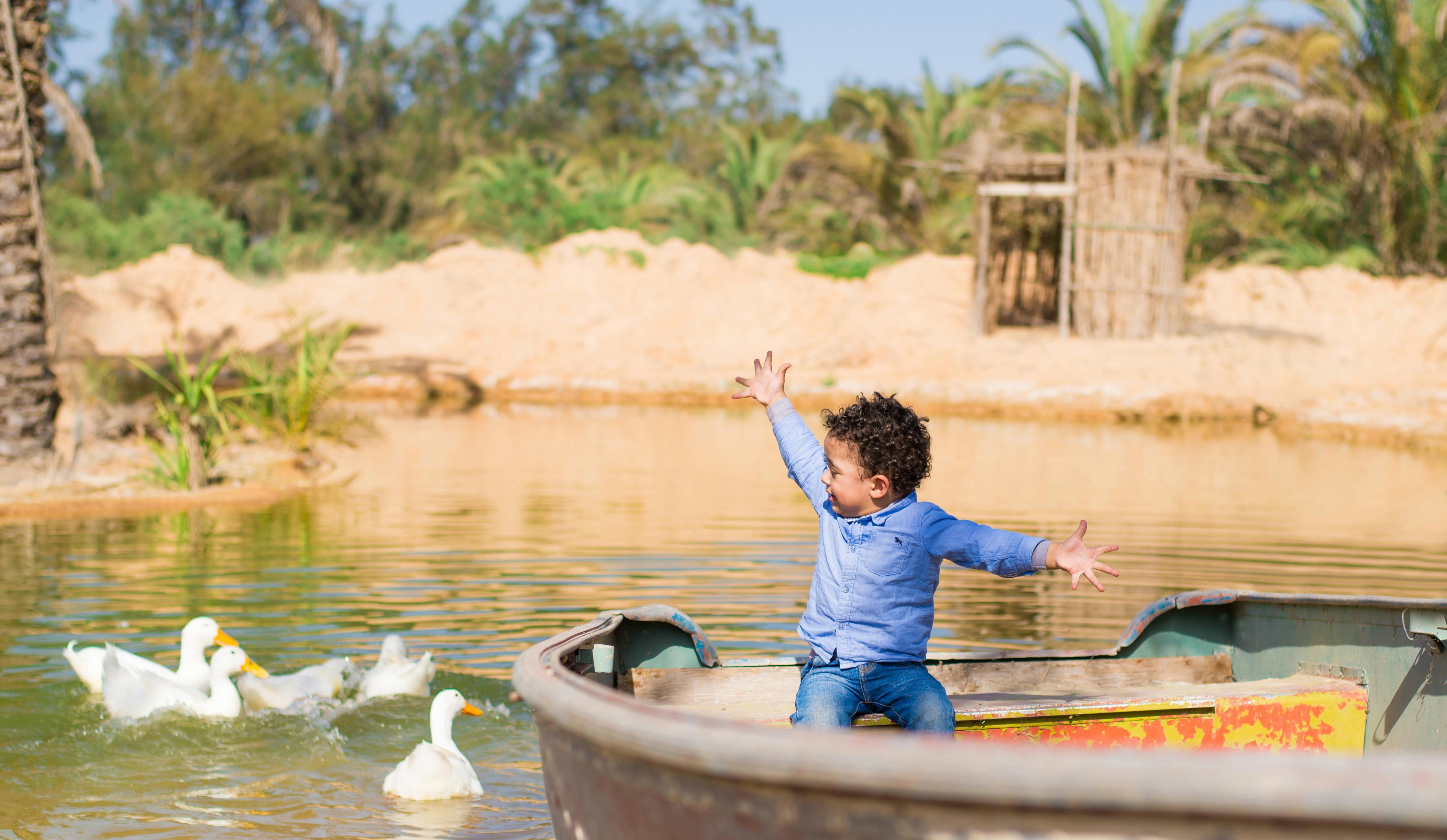 Boy Riding Boat on Body of Water · Free Stock Photo