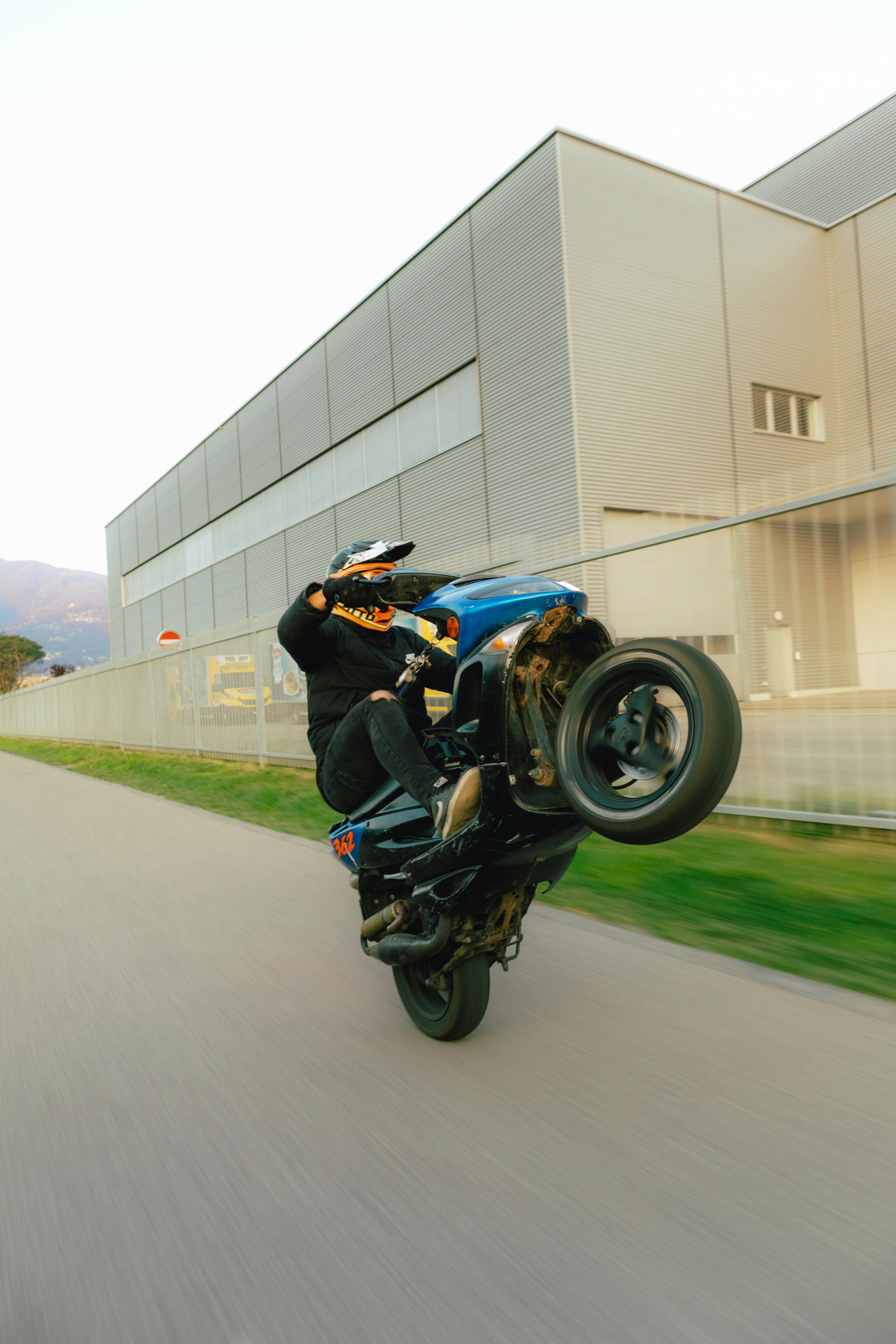 Scooter Driver Speeding Down the Street on One Wheel · Free Stock Photo