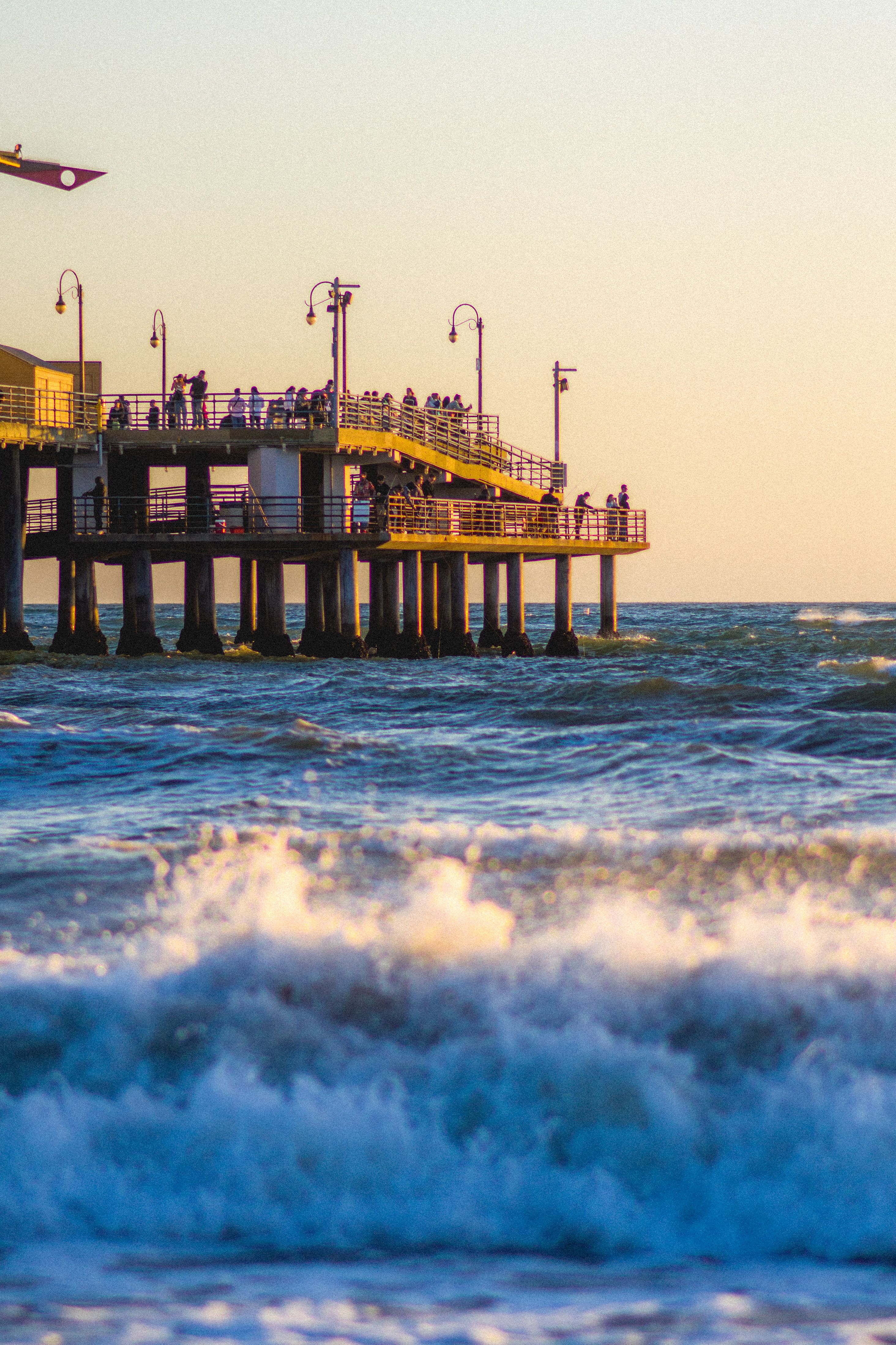 Waves Washing up the Shore near a Pier at Sunset · Free Stock Photo