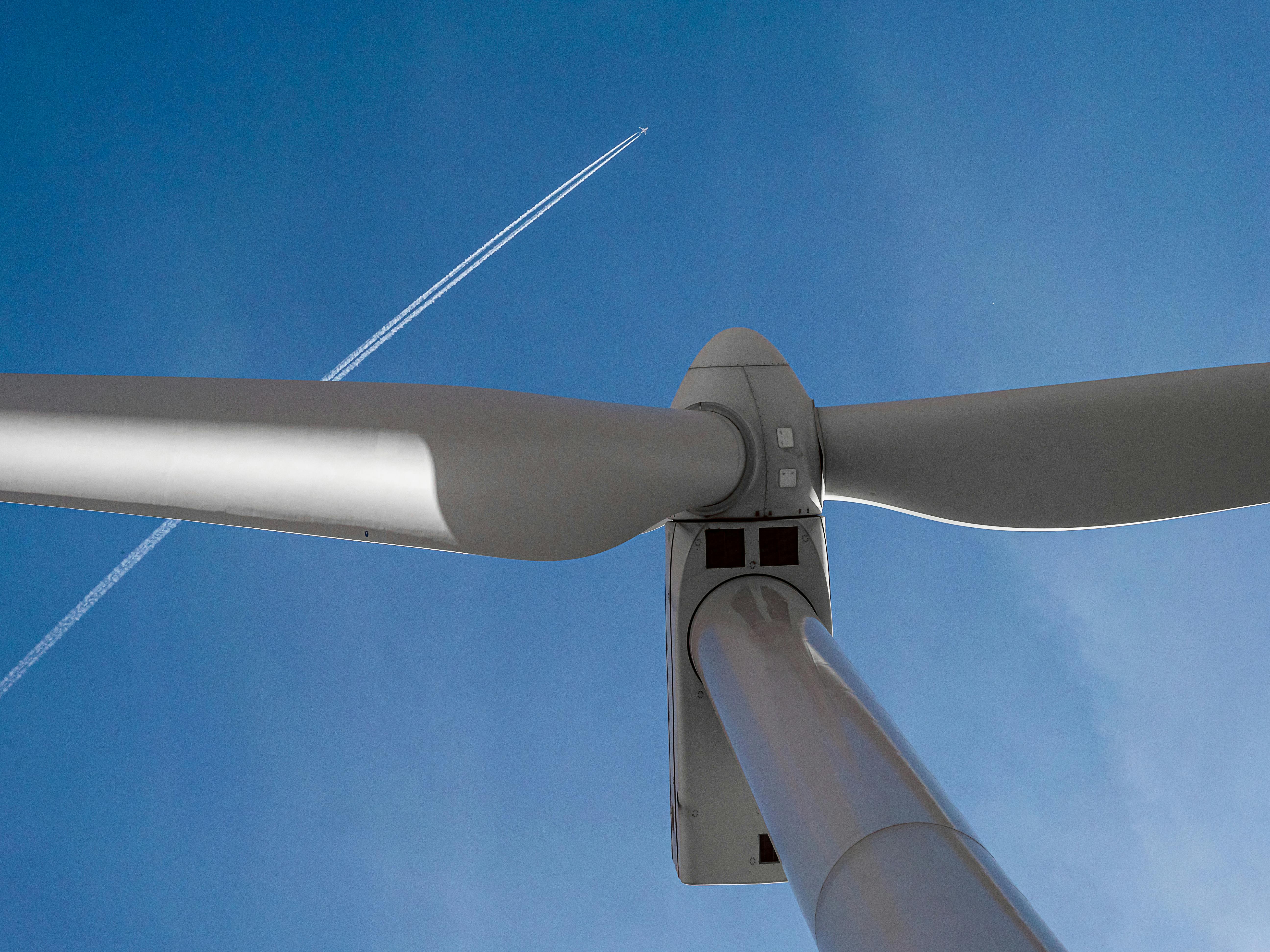 Jet Plane Flying over Wind Turbine · Free Stock Photo