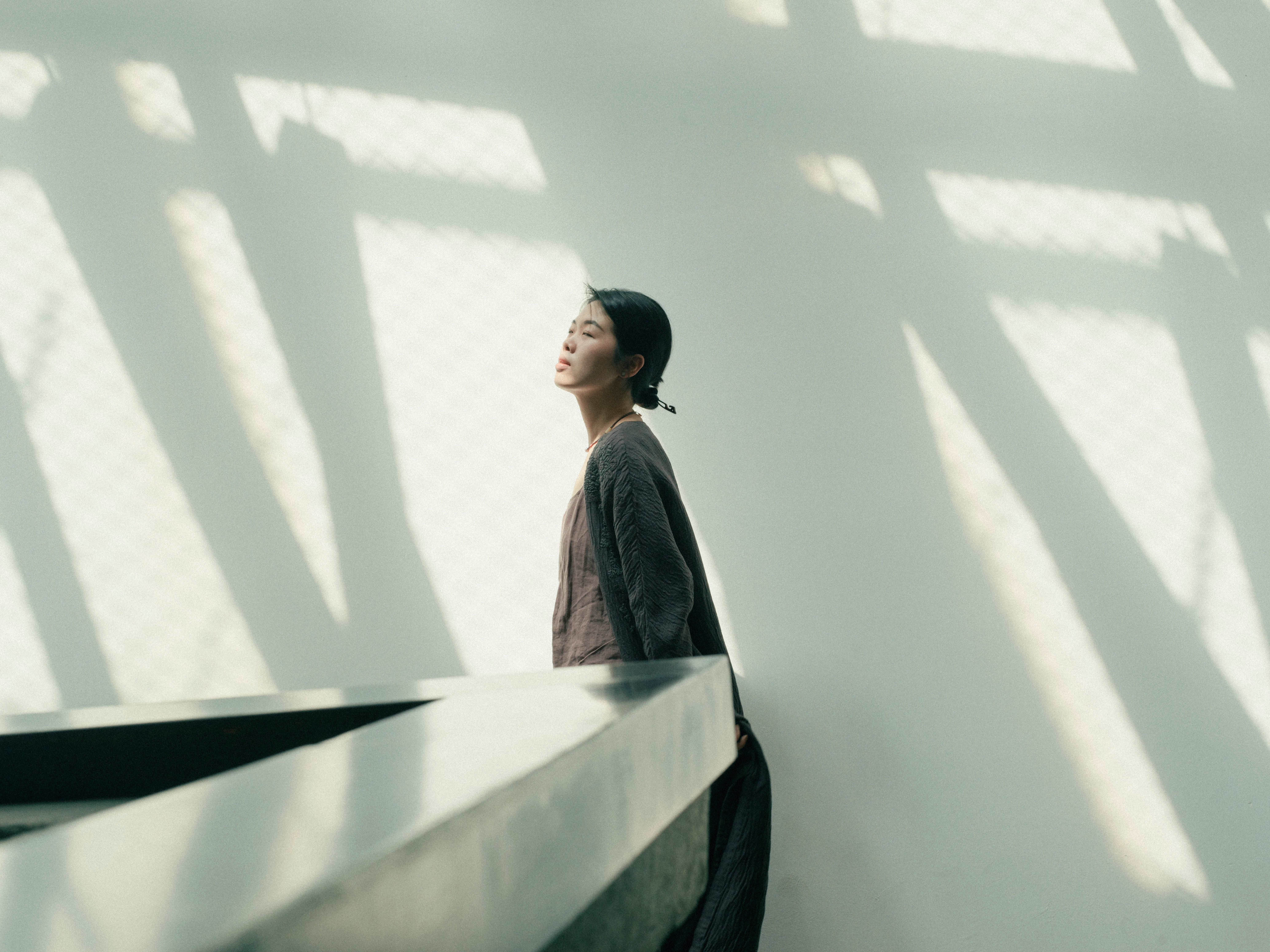 Brunette Woman Posing in Shadow Against White Wall · Free Stock Photo