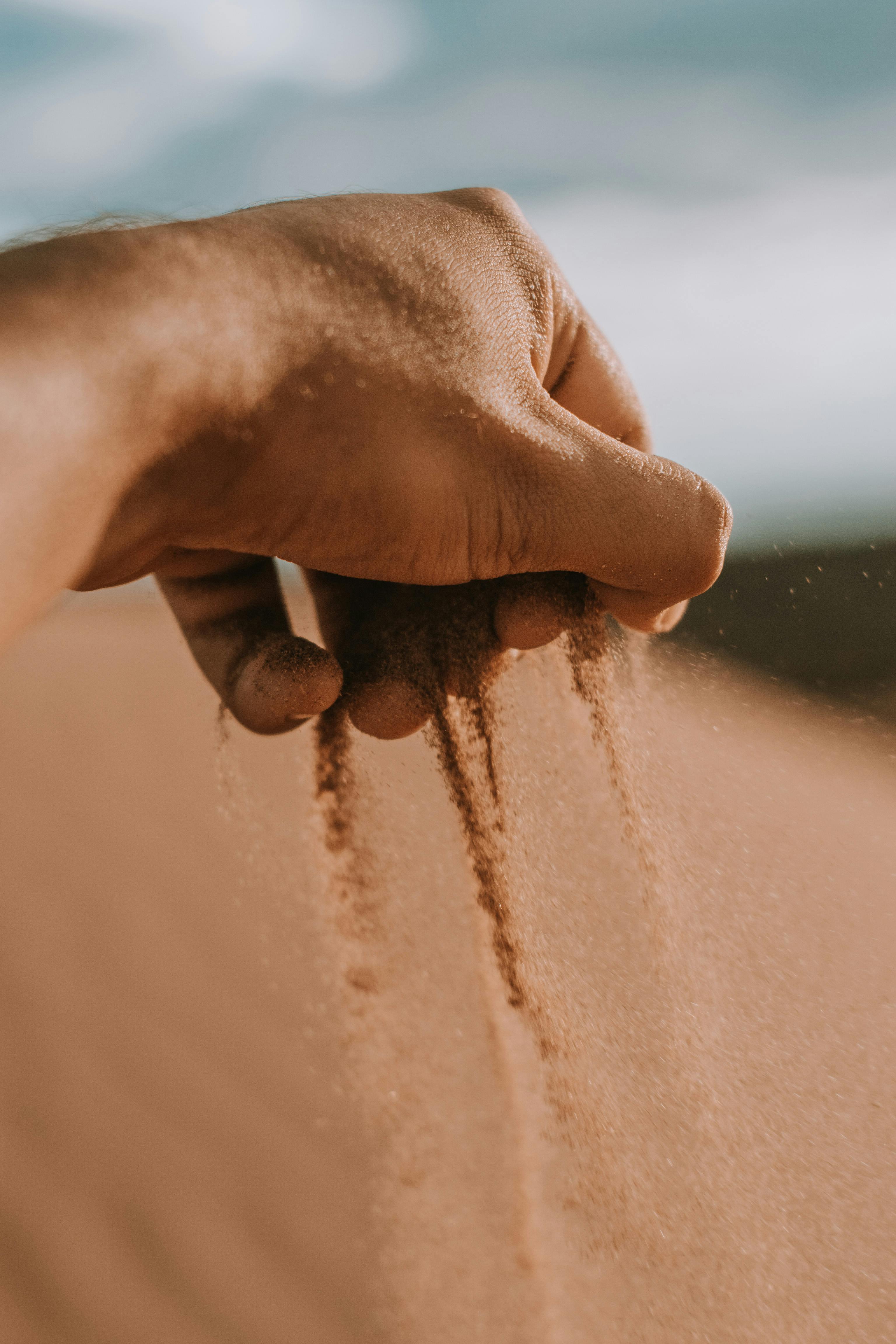 Mans Hand Scattering Sand over the Beach · Free Stock Photo