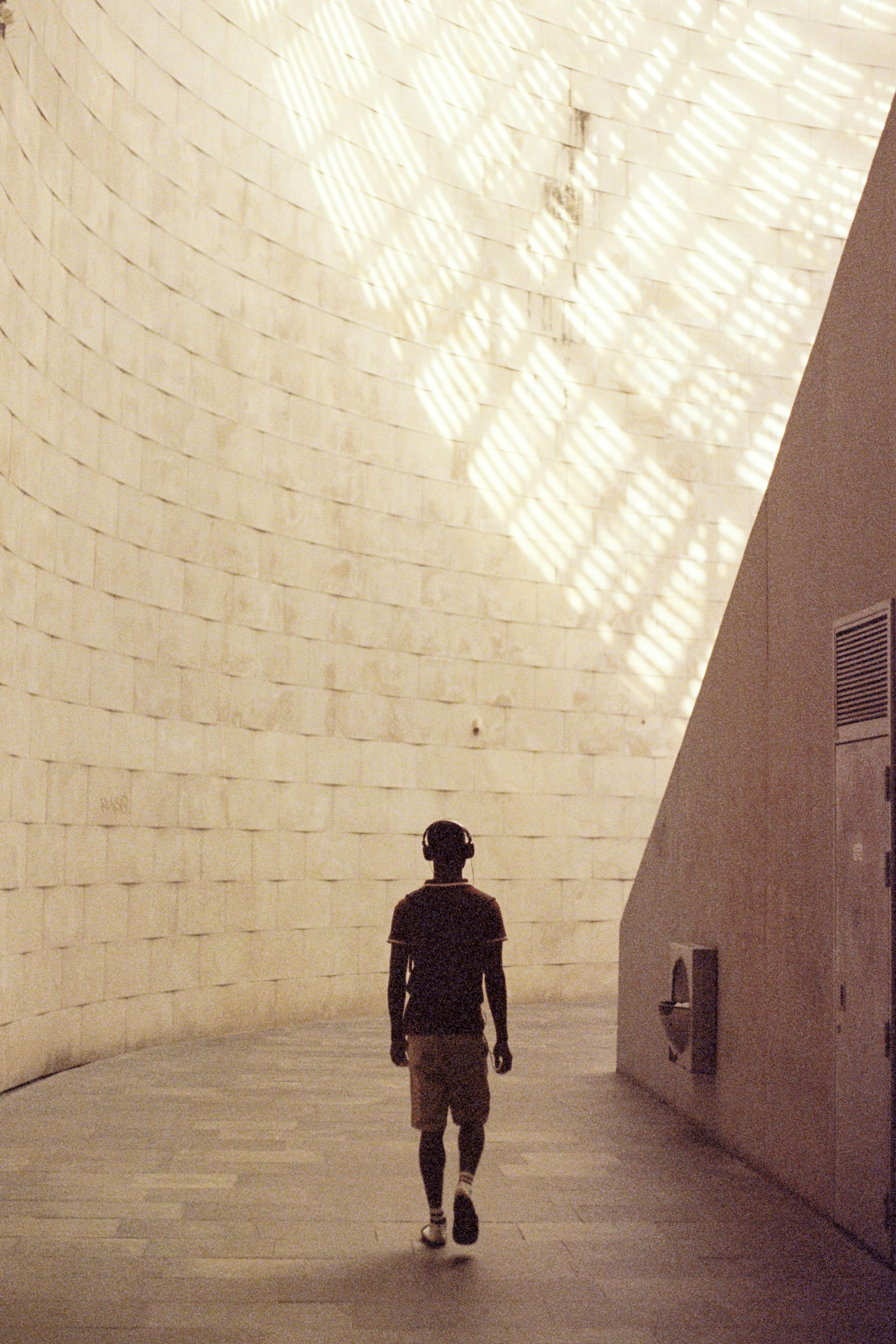 Man in Headphones Surrounded by High Windowless Walls · Free Stock Photo