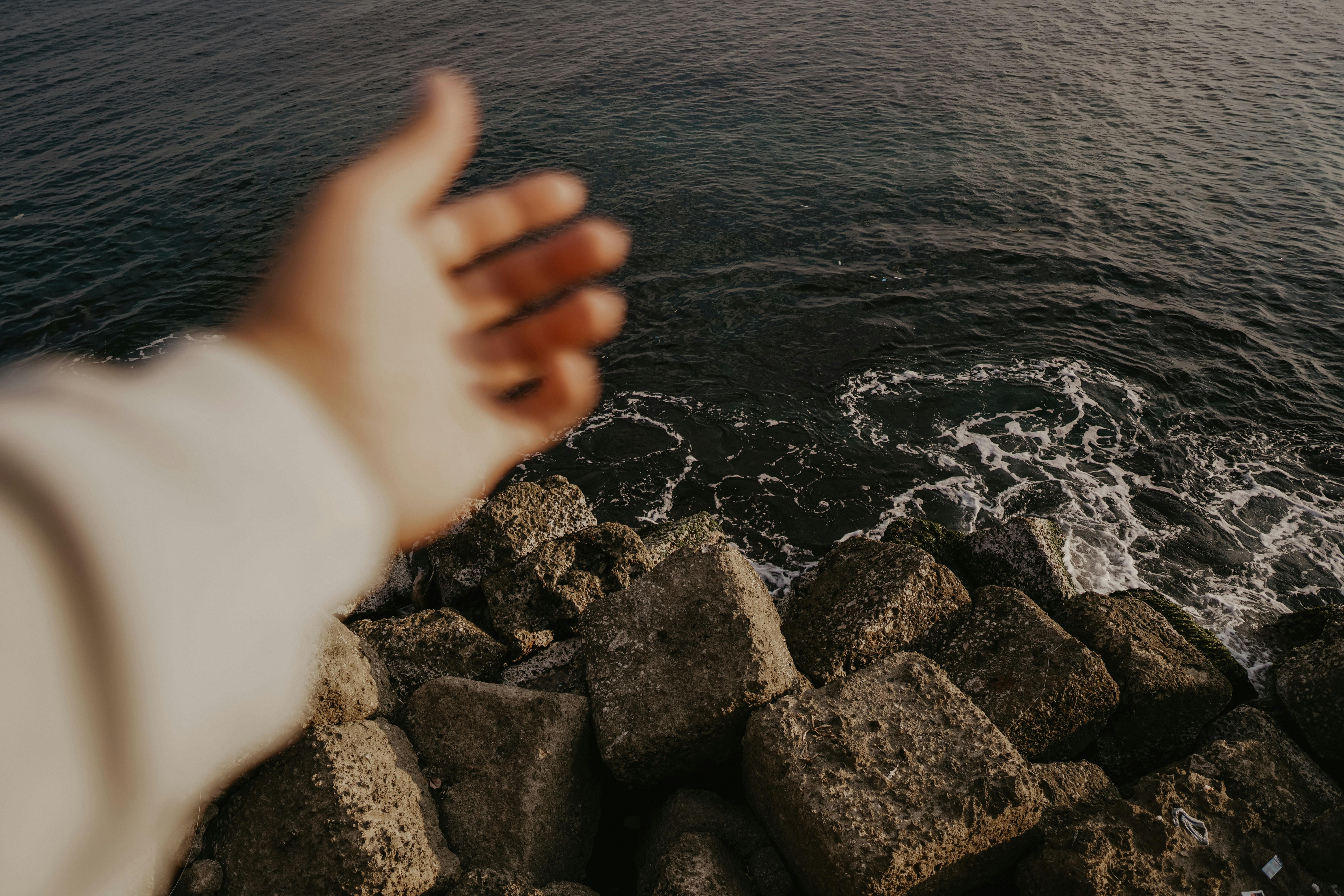 Hand over Rocky Seashore · Free Stock Photo
