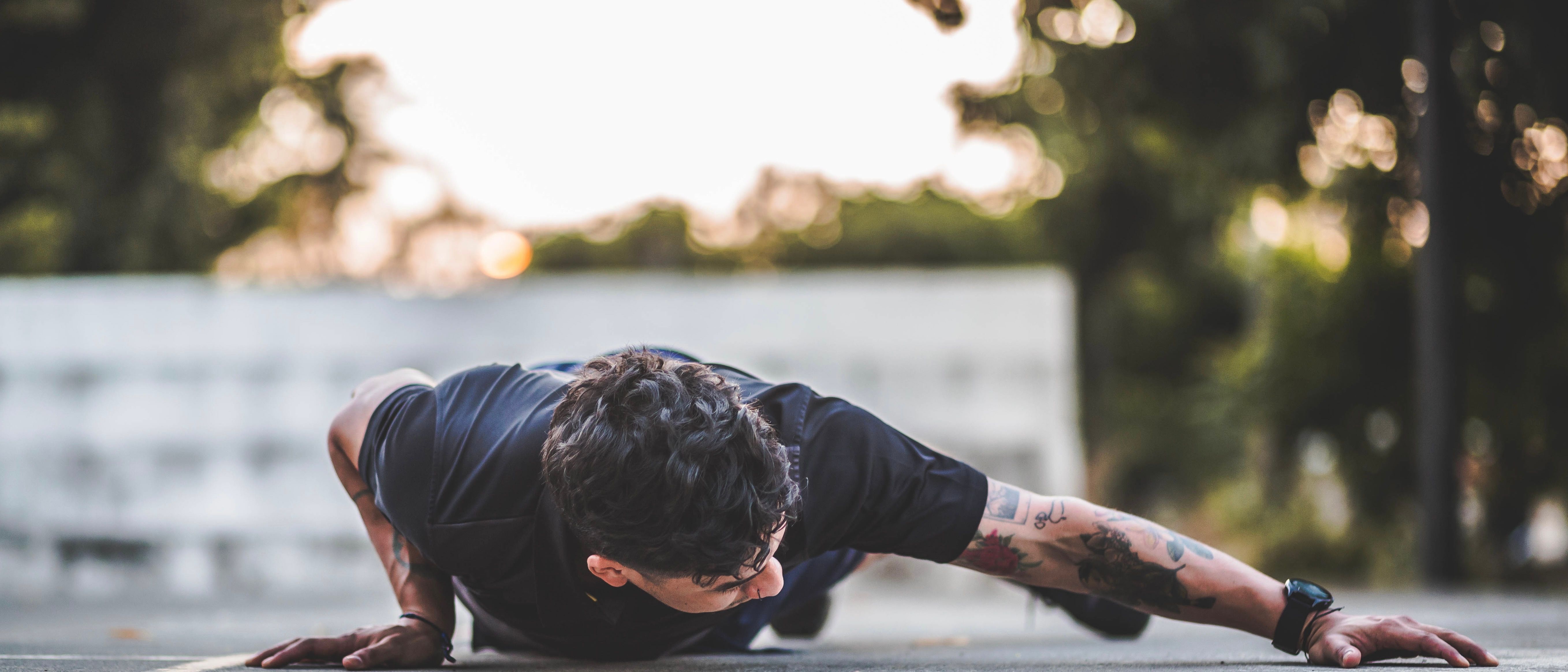 Man with Tattoos Leaning over the Surface Outdoors · Free Stock Photo