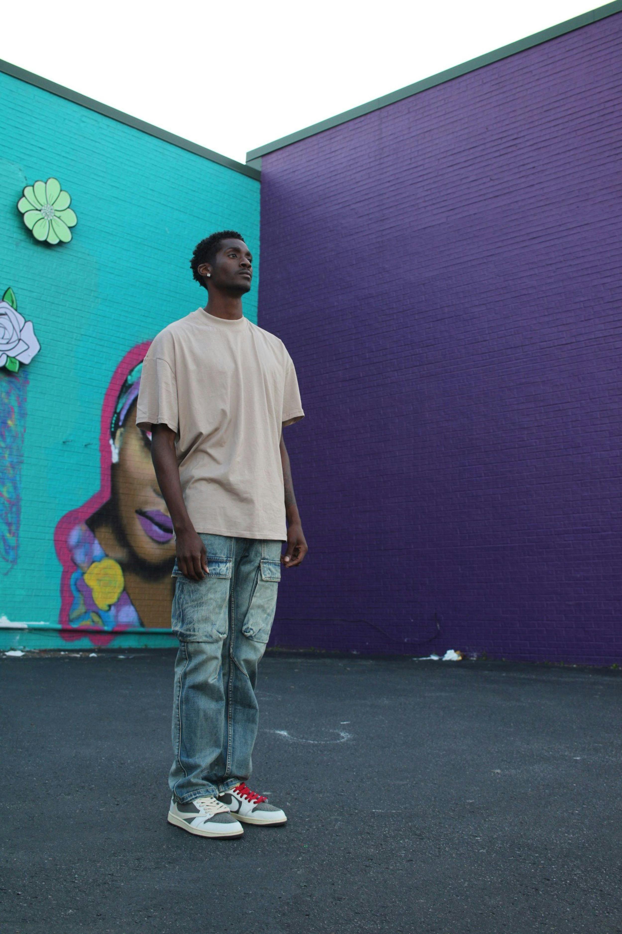 Man in T-Shirt and Jeans Standing by Mural on Wall · Free Stock Photo