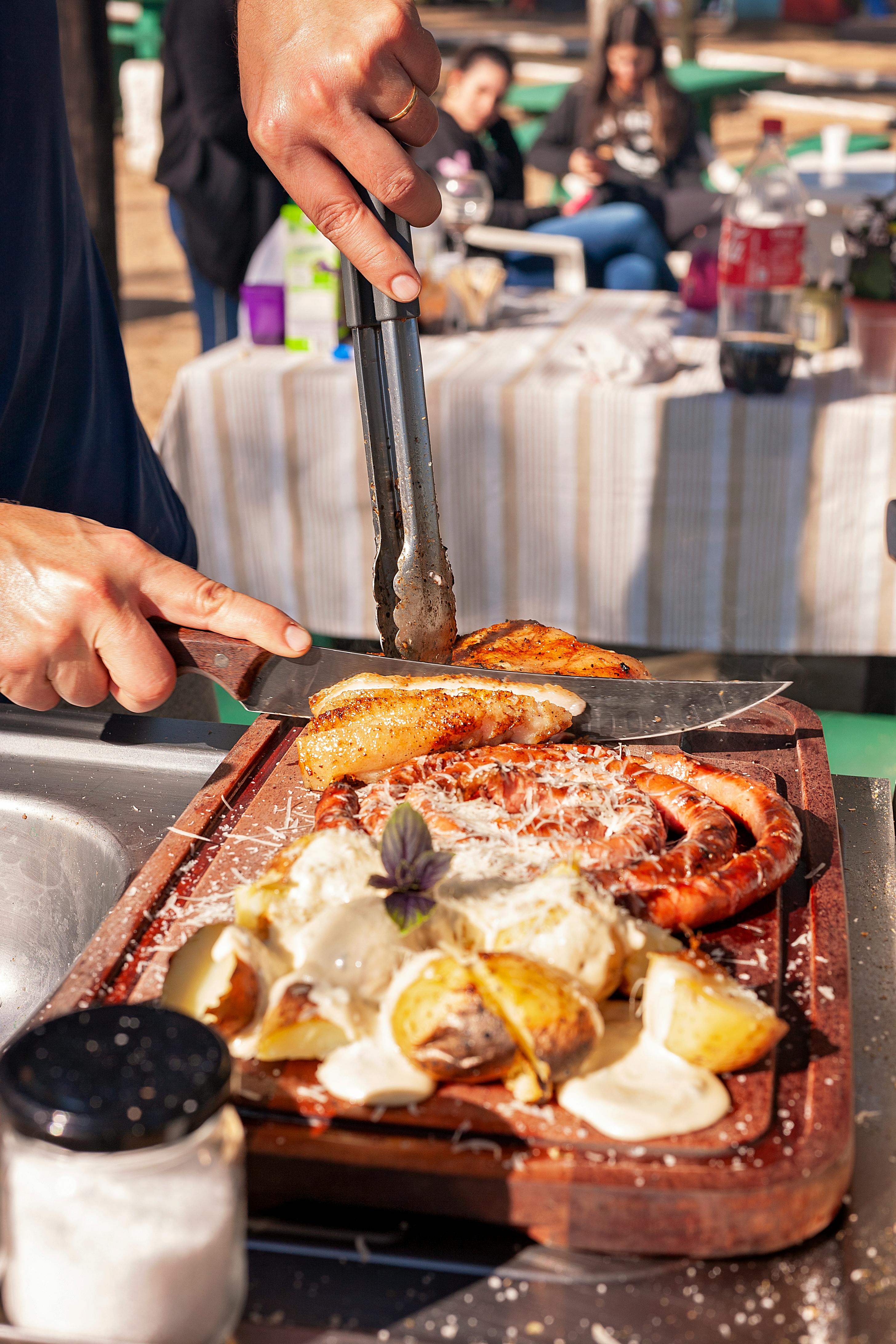 Man Cutting Meat on Wooden Cutting Board · Free Stock Photo