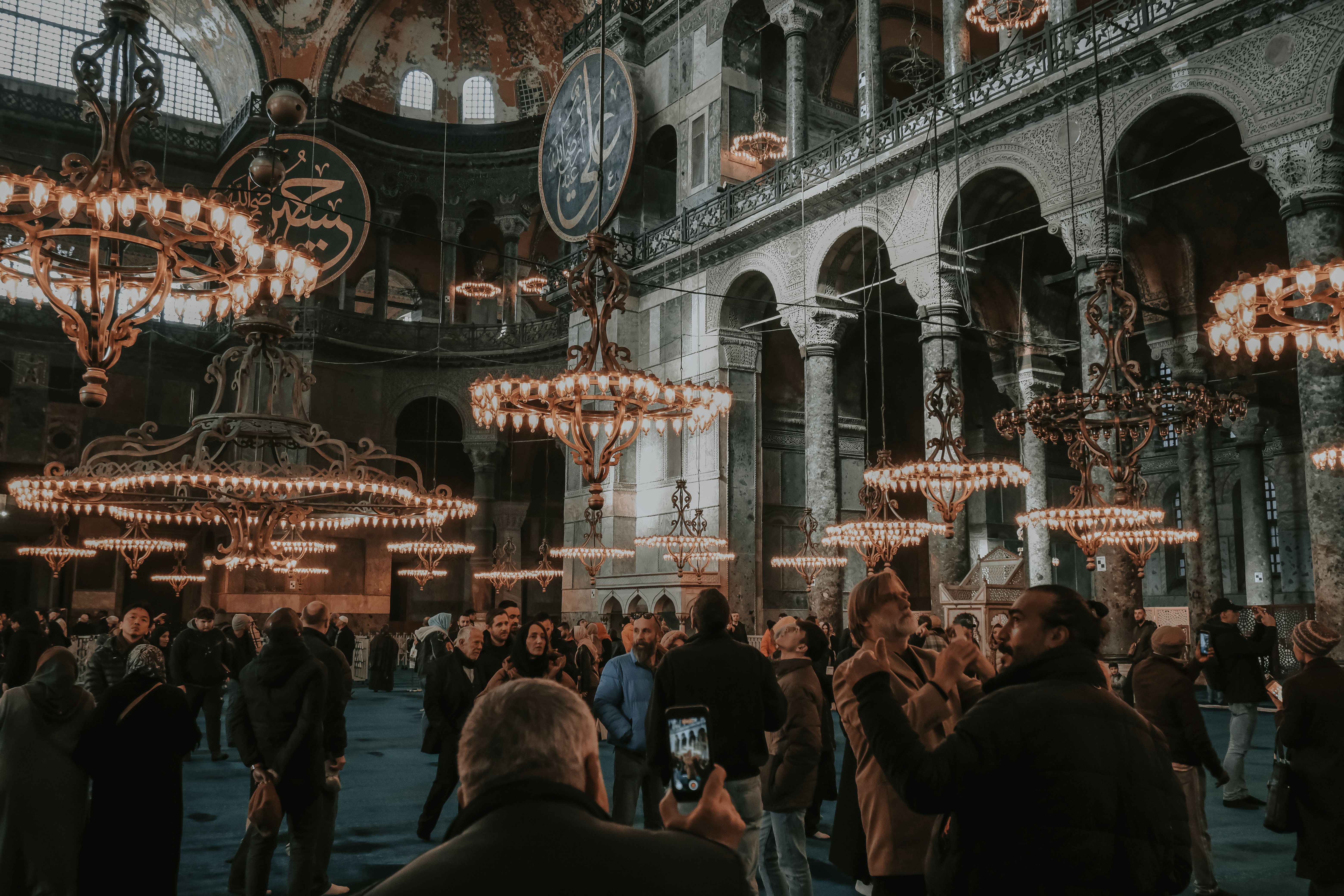 People are standing in a large room with chandeliers · Free Stock Photo