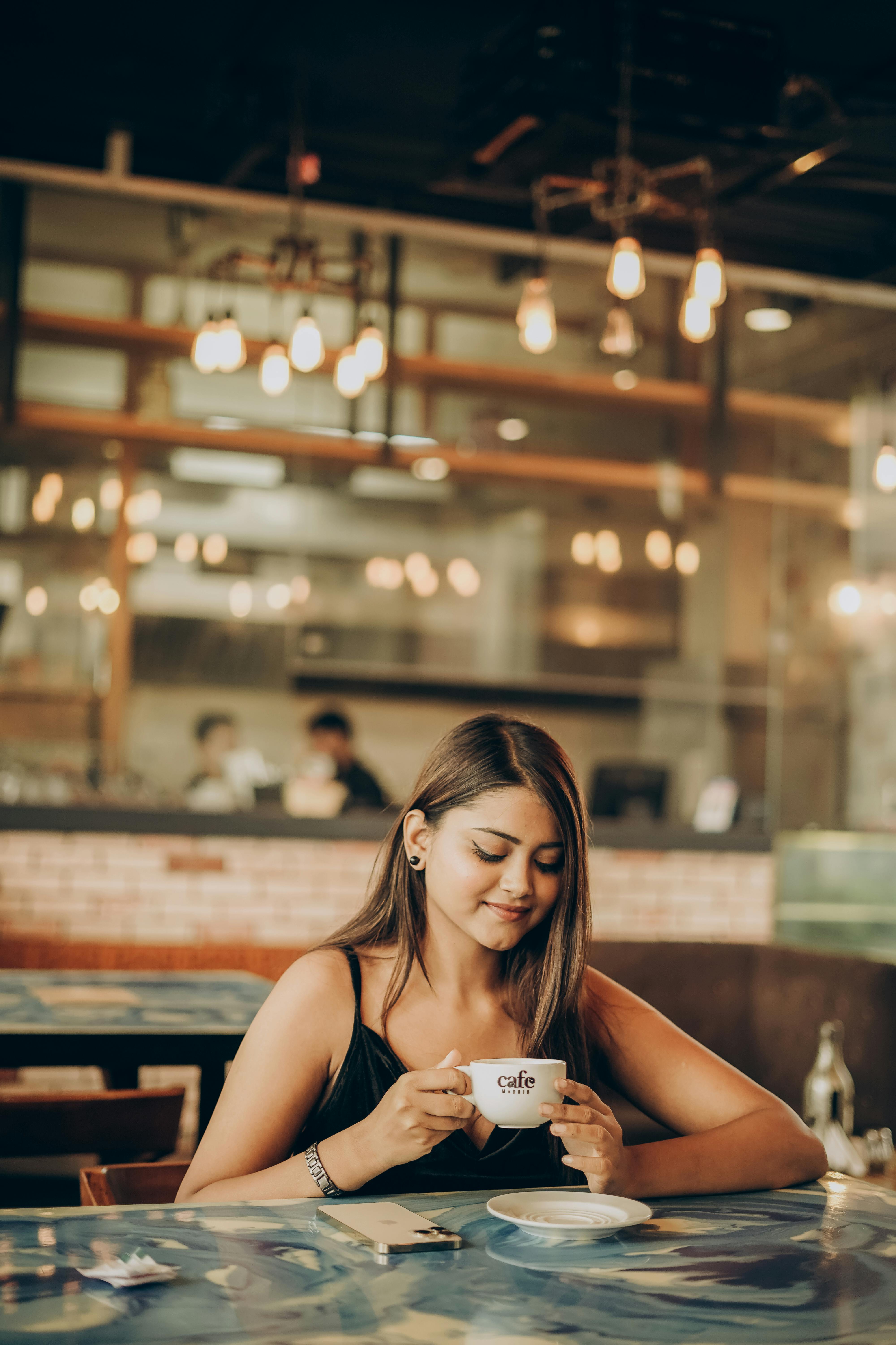 Young Woman Sitting in a Cafe with a Cup of Coffee · Free Stock Photo