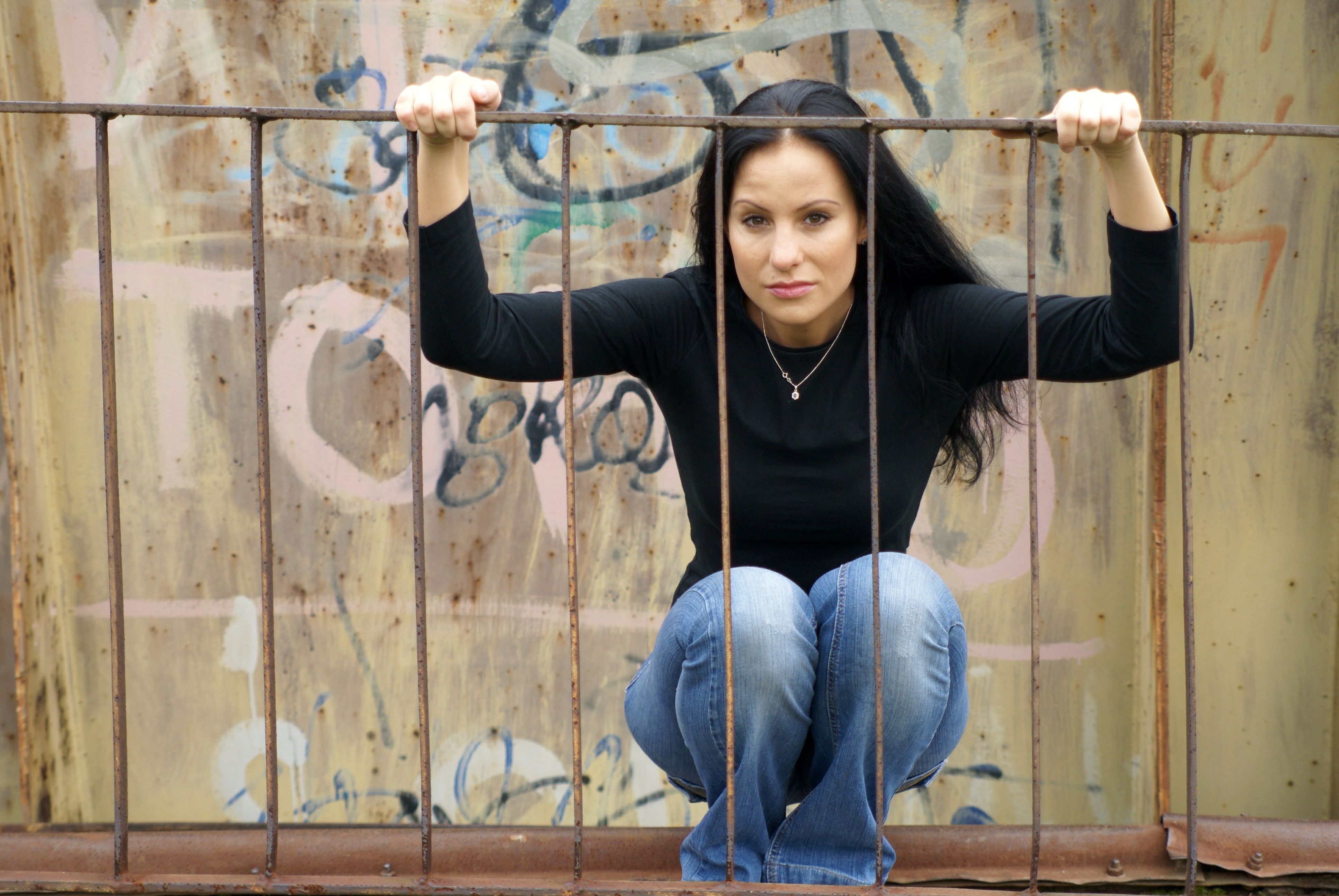 A woman is leaning over a metal fence · Free Stock Photo