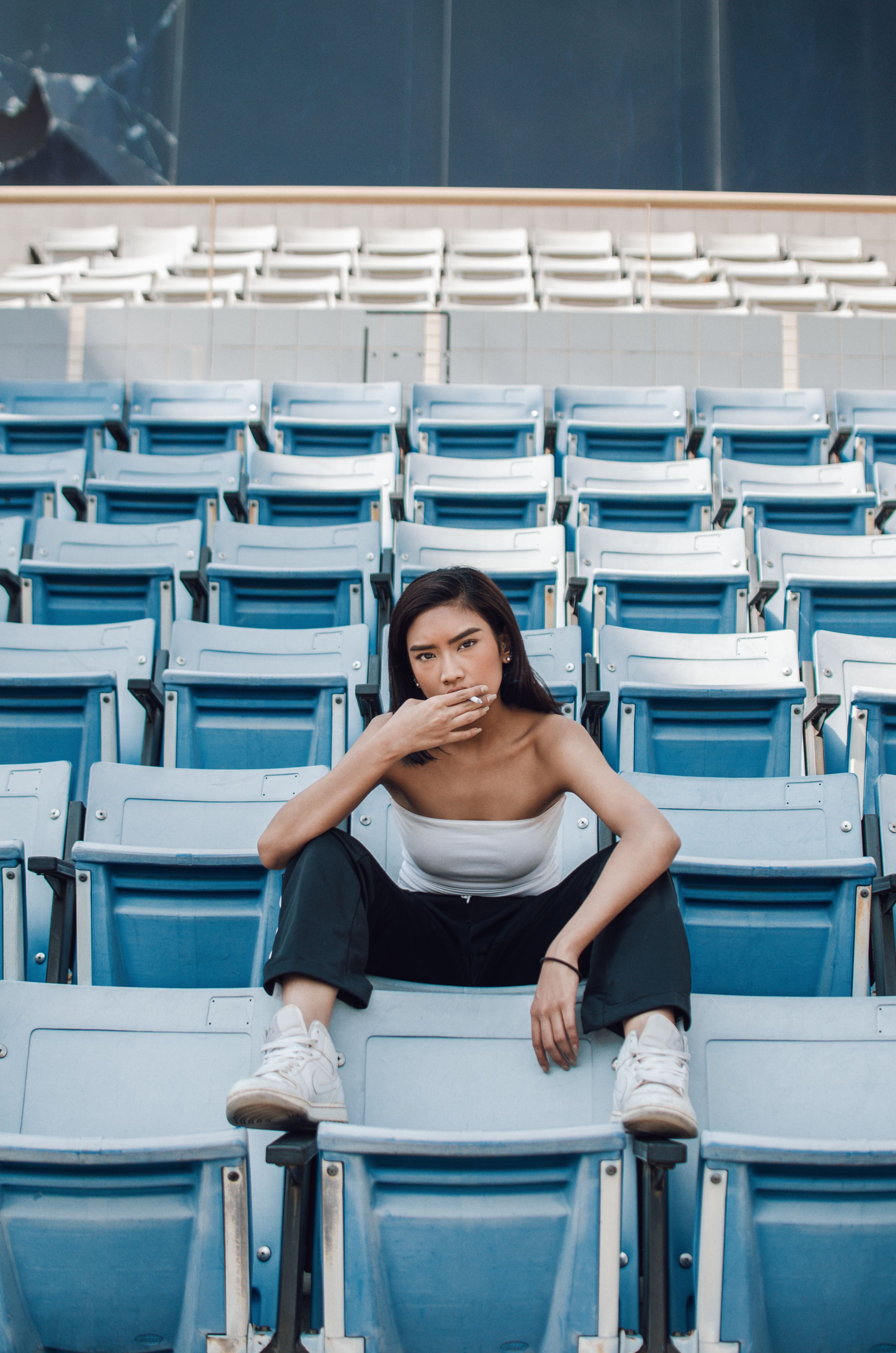 Woman Sitting in Stadium and Smoking · Free Stock Photo