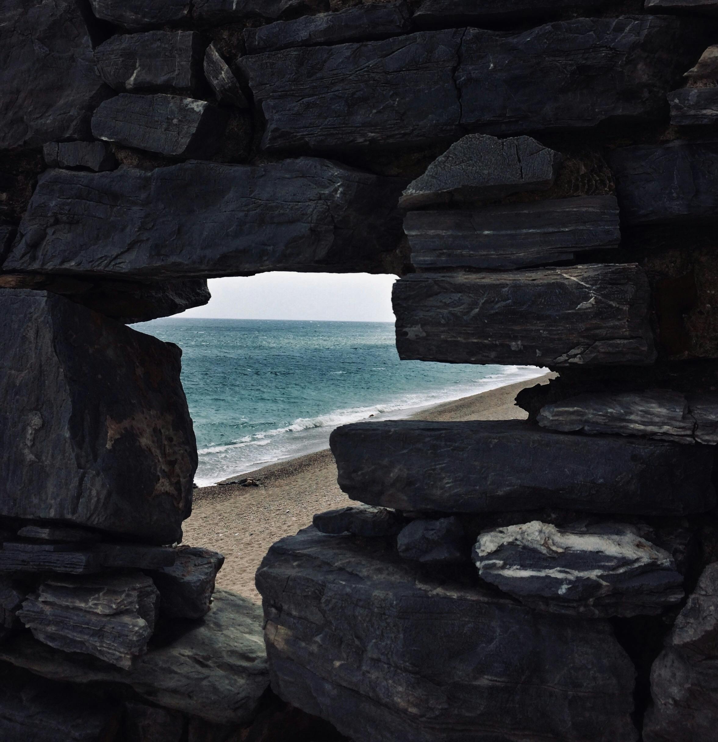 Beach and Sea behind Hole in Stone Wall · Free Stock Photo