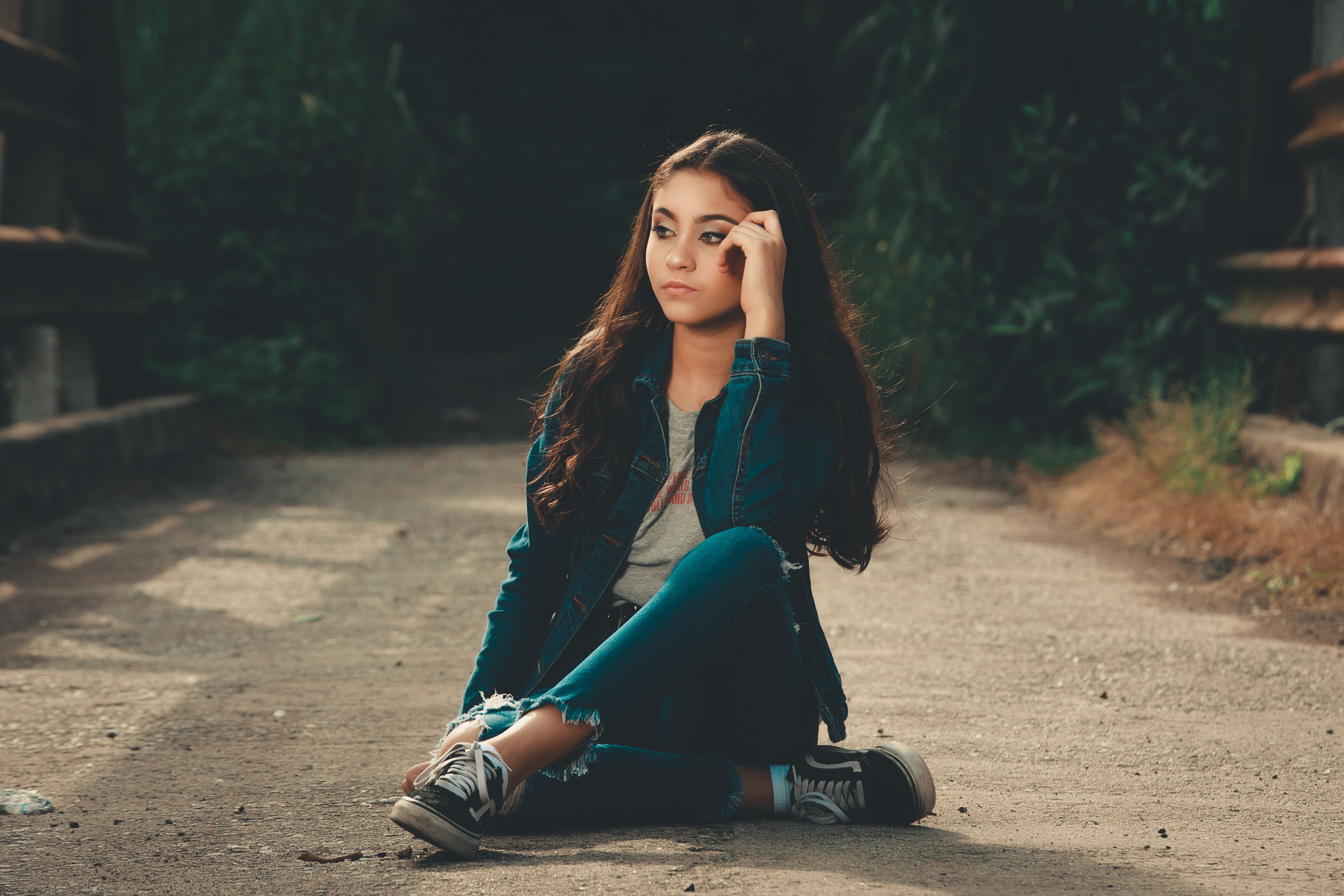 Sensitive woman sitting on paved walkway in park · Free Stock Photo
