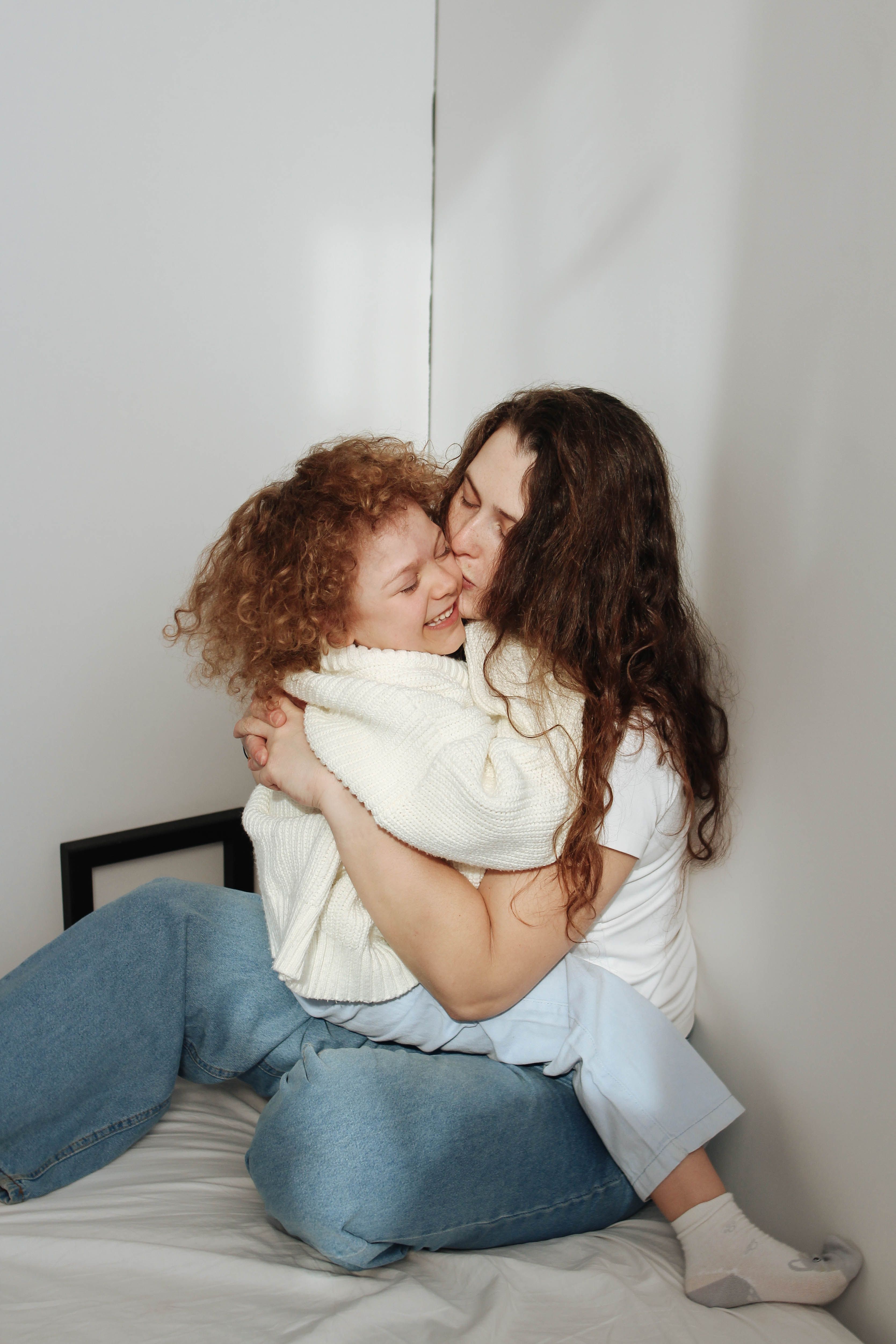 Happy Woman Cuddling with Child on Sofa · Free Stock Photo