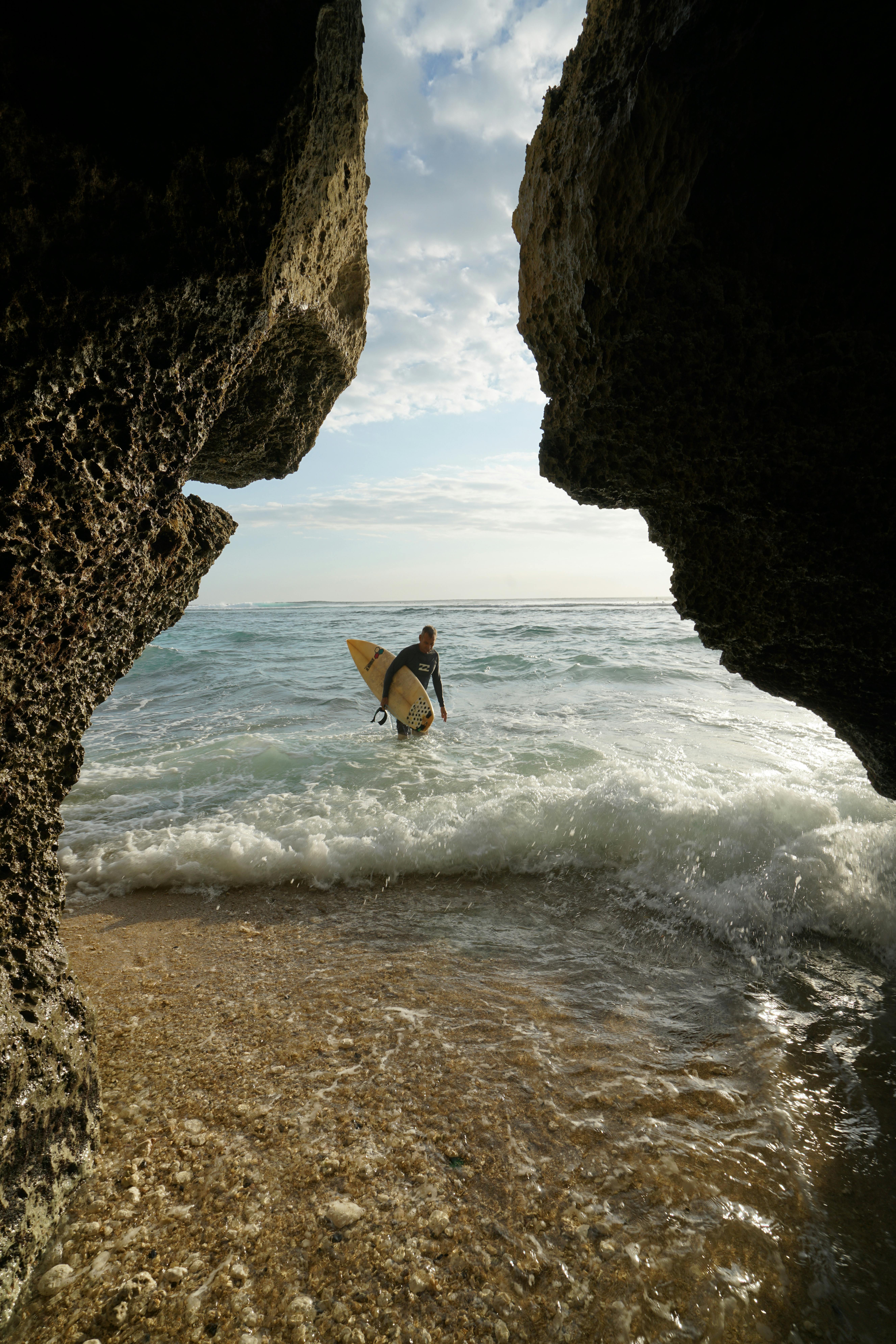 Man Emerging from Sea Carrying Surfboard · Free Stock Photo
