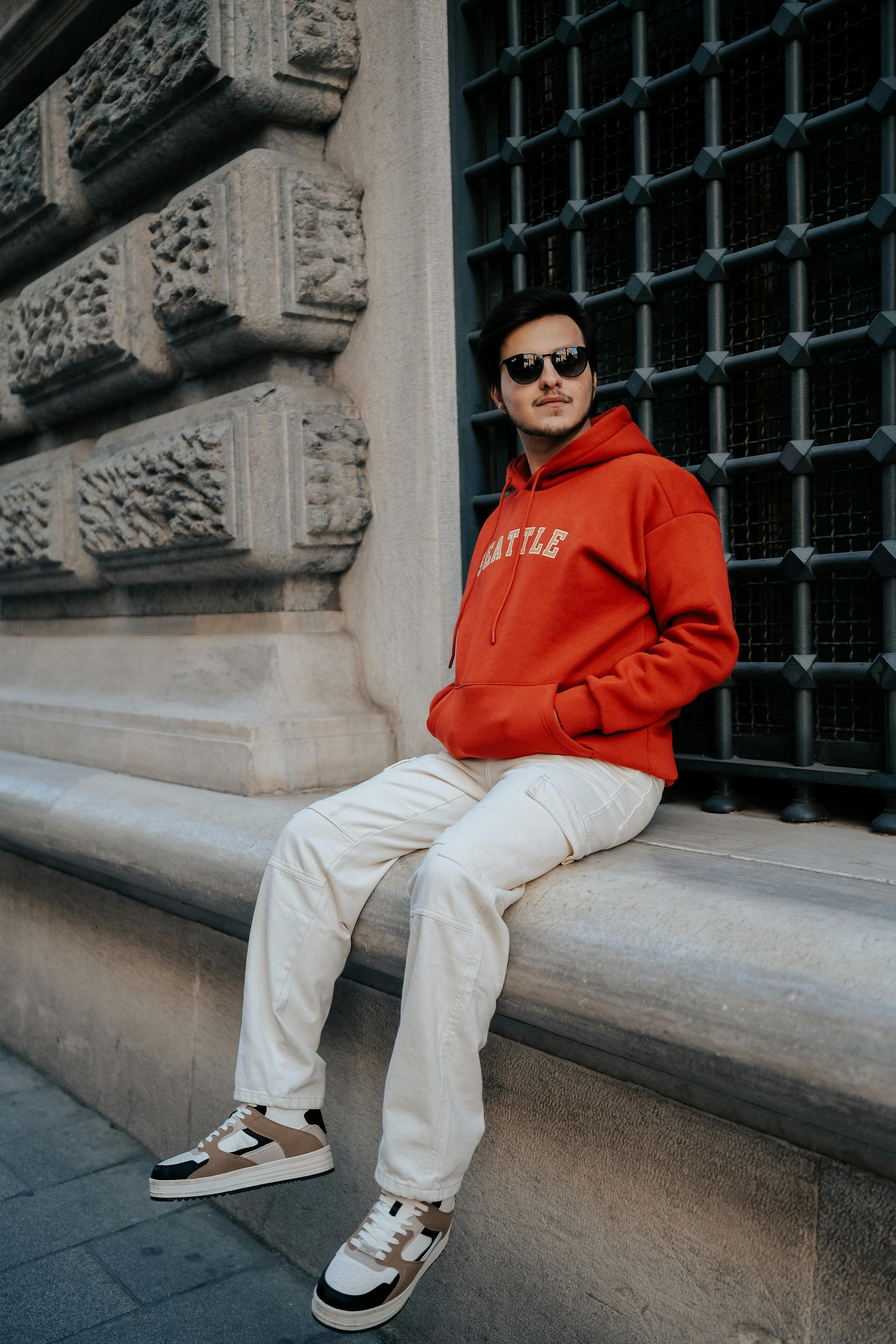 Man in Red Hoodie Sitting on Wall · Free Stock Photo
