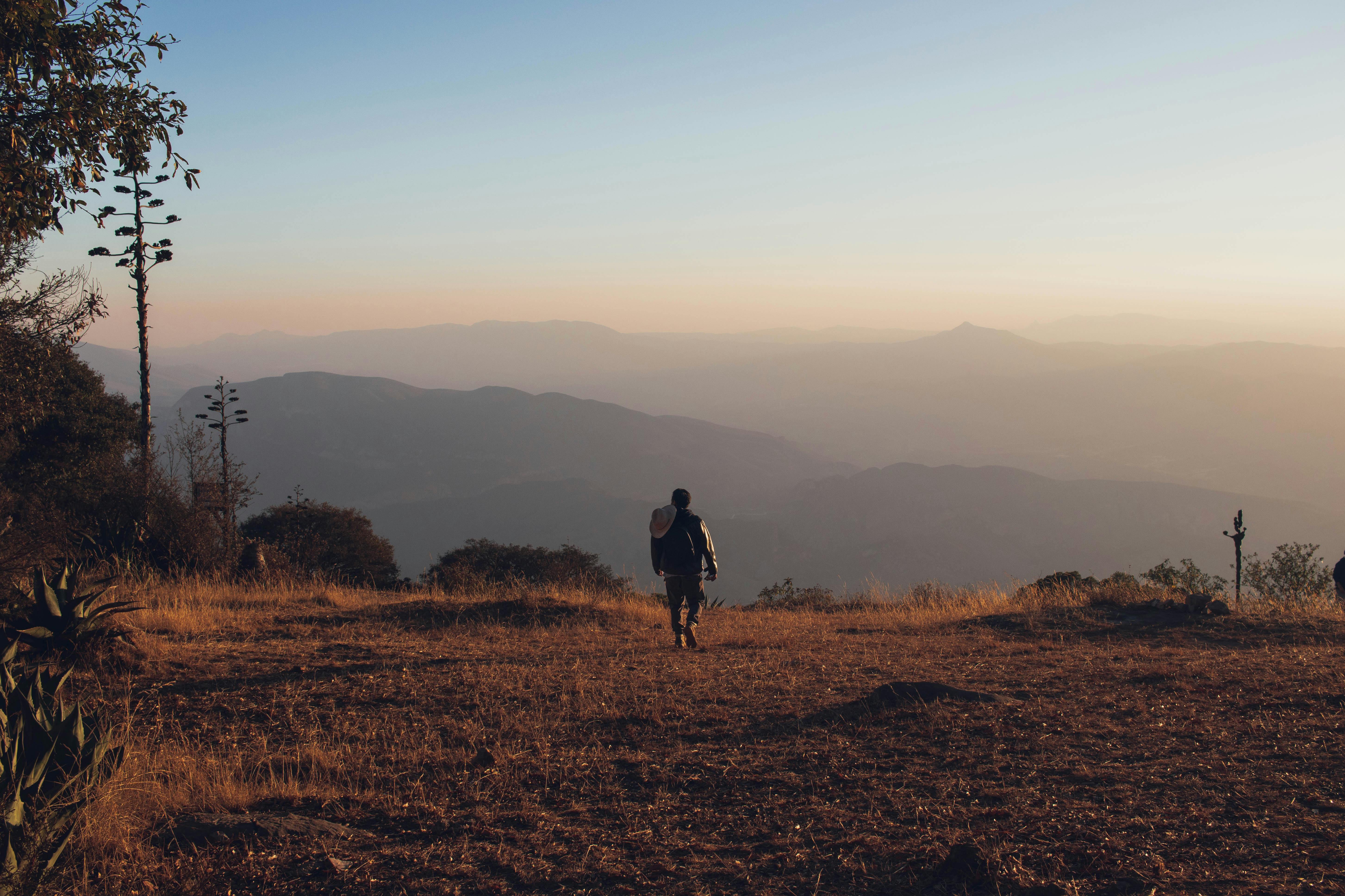 A person walking on a hill with mountains in the background · Free ...