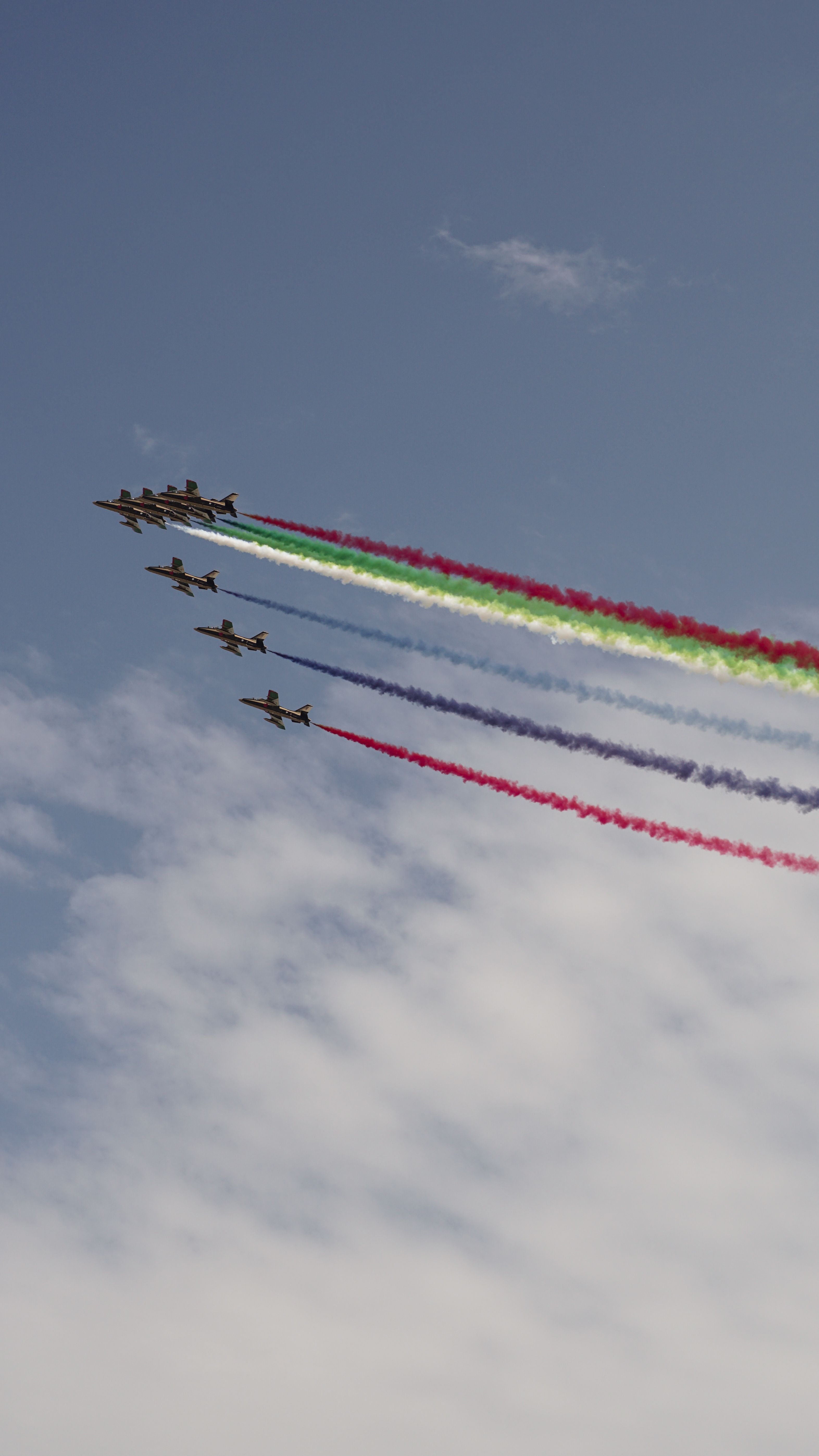 Four jets flying in formation with red, white and green smoke trails ...