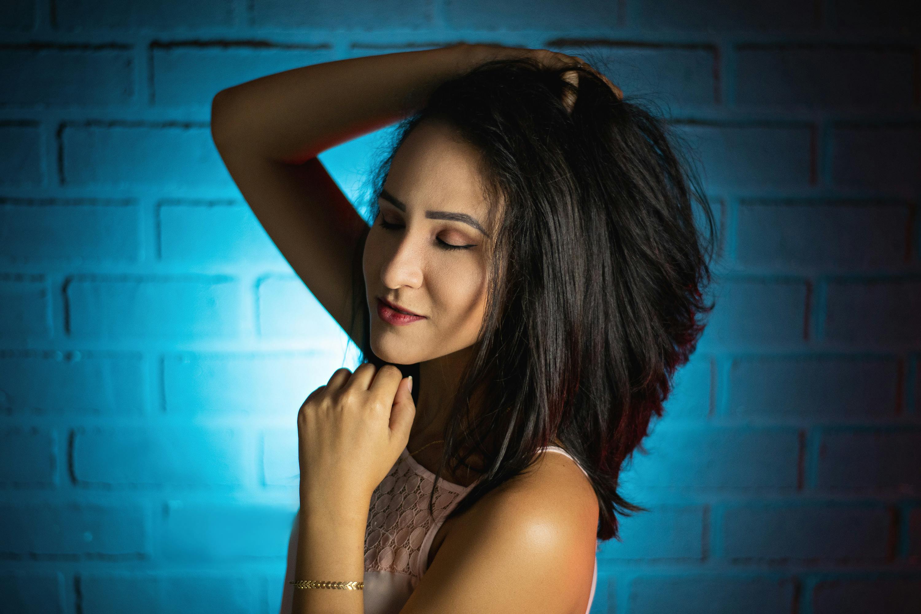 Portrait of Woman Standing under Blue Light in front of Brick Wall ...