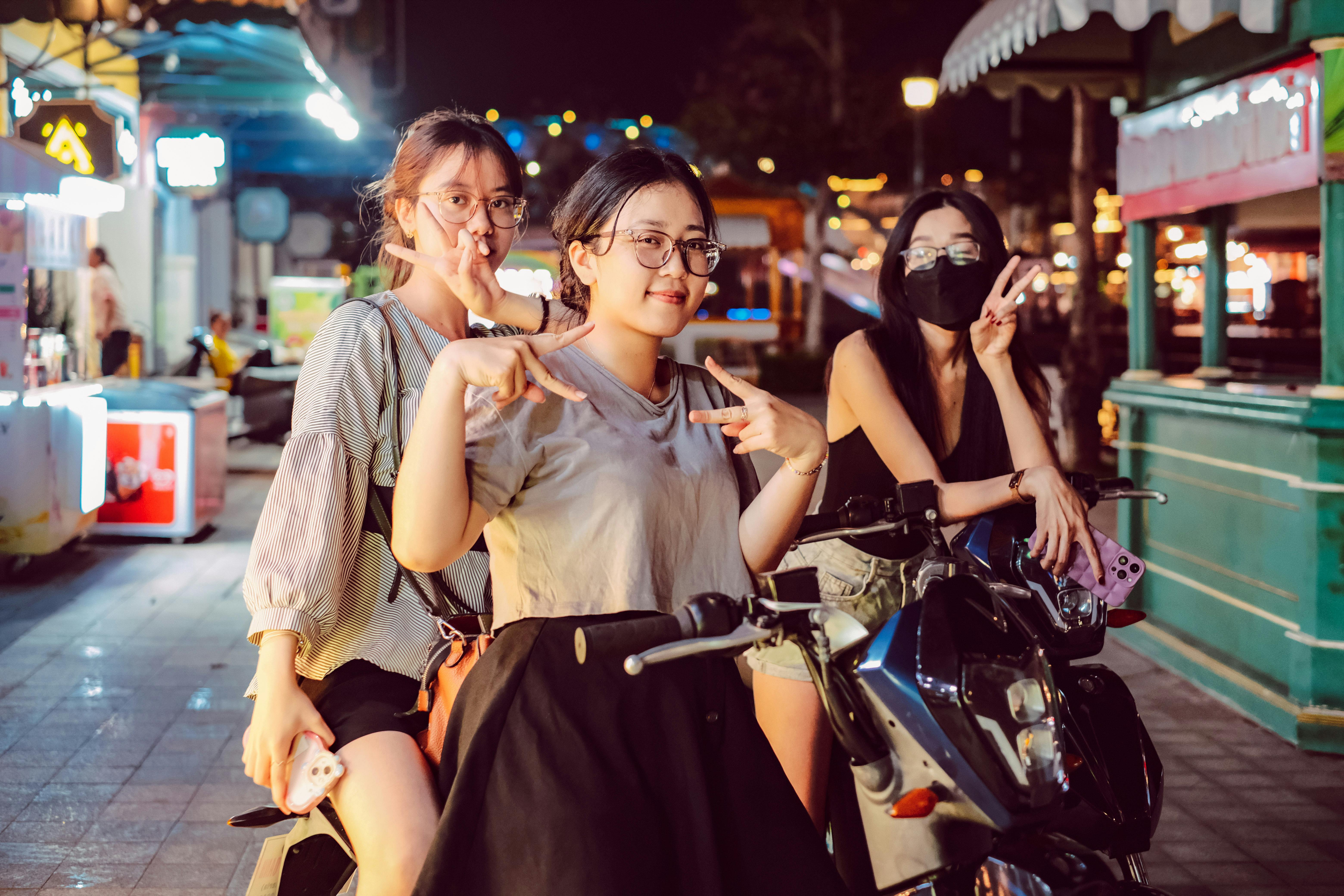 Women Posing on Scooters on Street Market at Night · Free Stock Photo