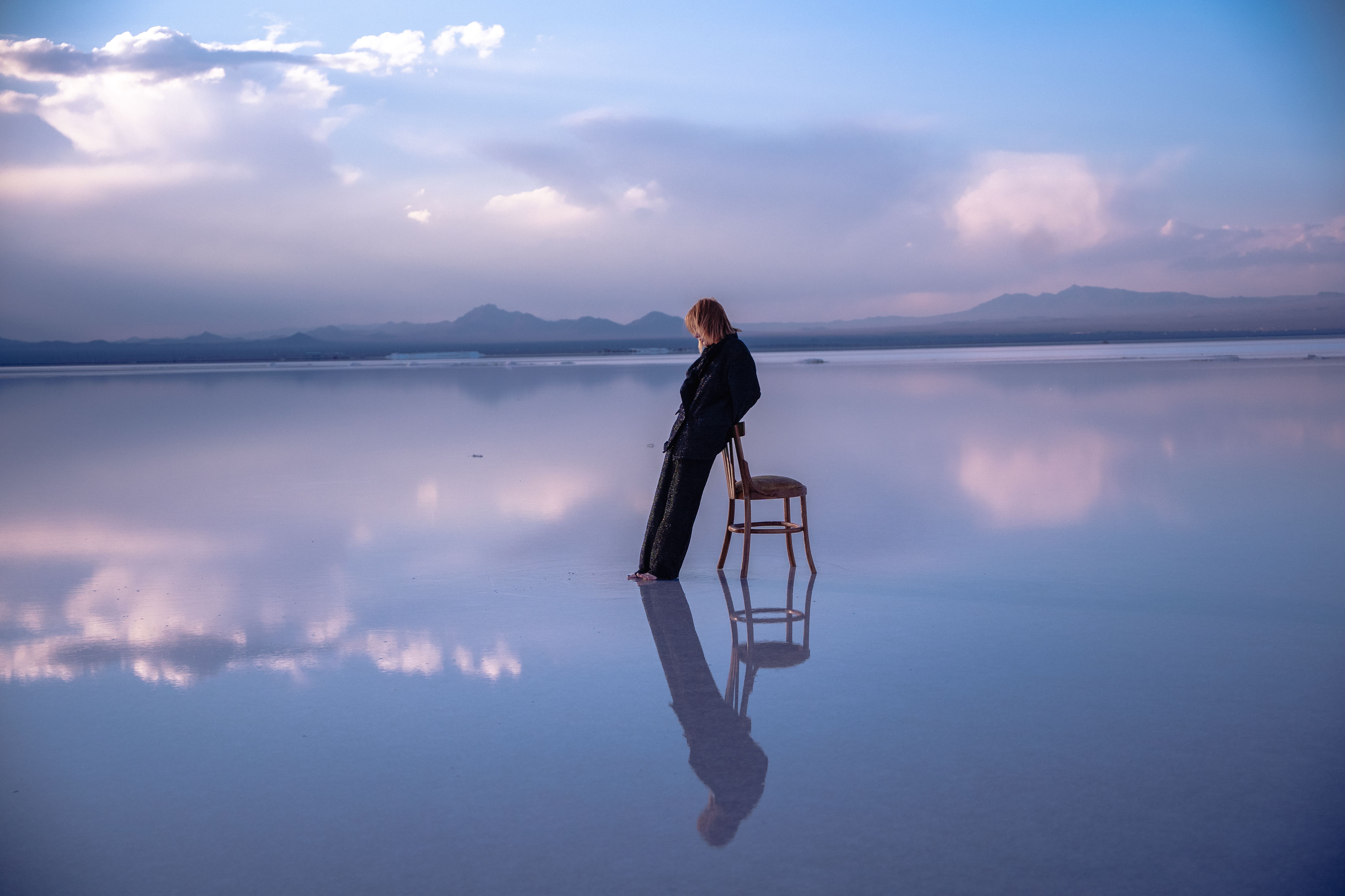 Woman Leaning on Chair on Shallow Water · Free Stock Photo
