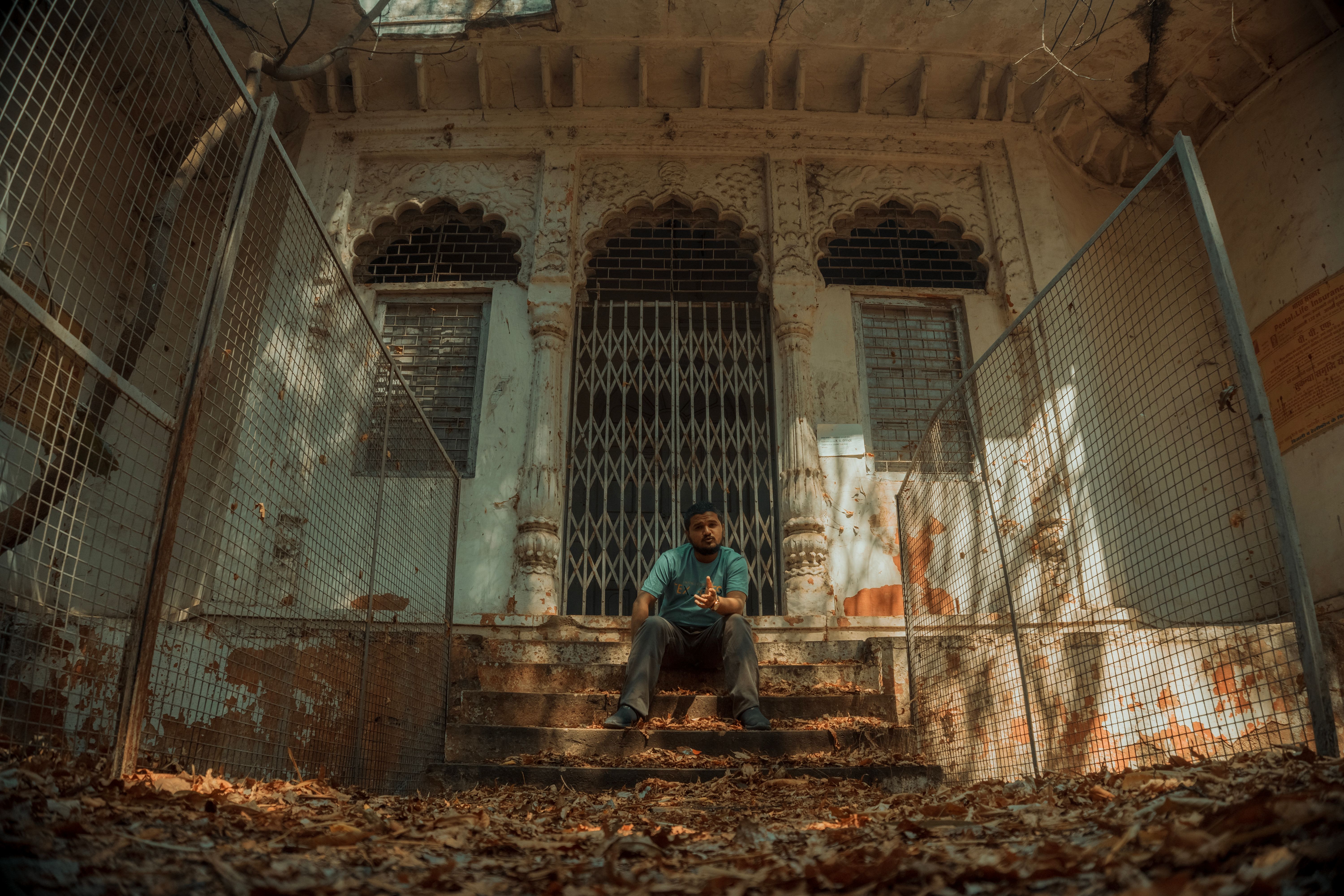Man Sitting in Entrance to Abandoned Building · Free Stock Photo