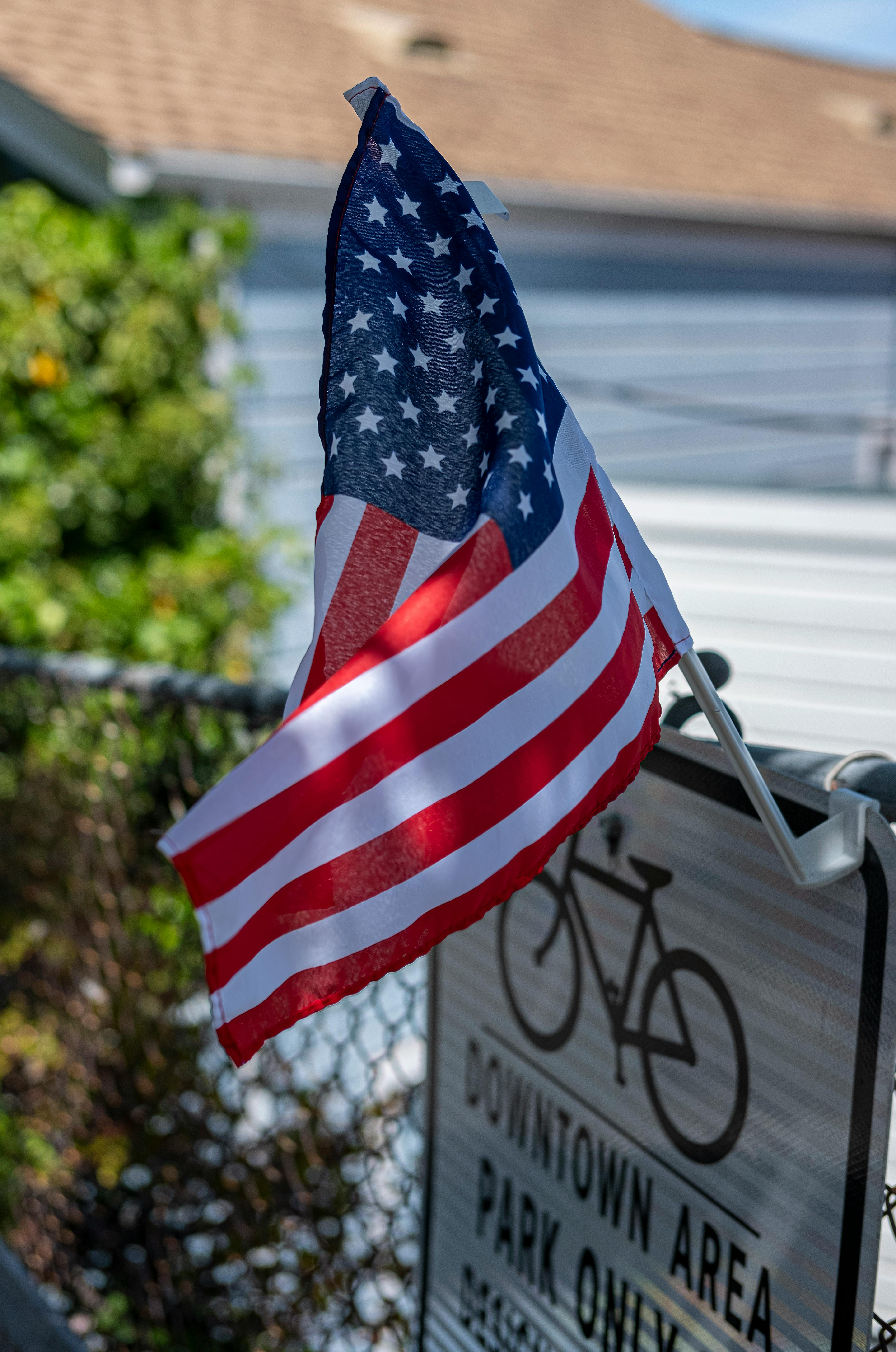 American Flag over Road Sign on Fence · Free Stock Photo