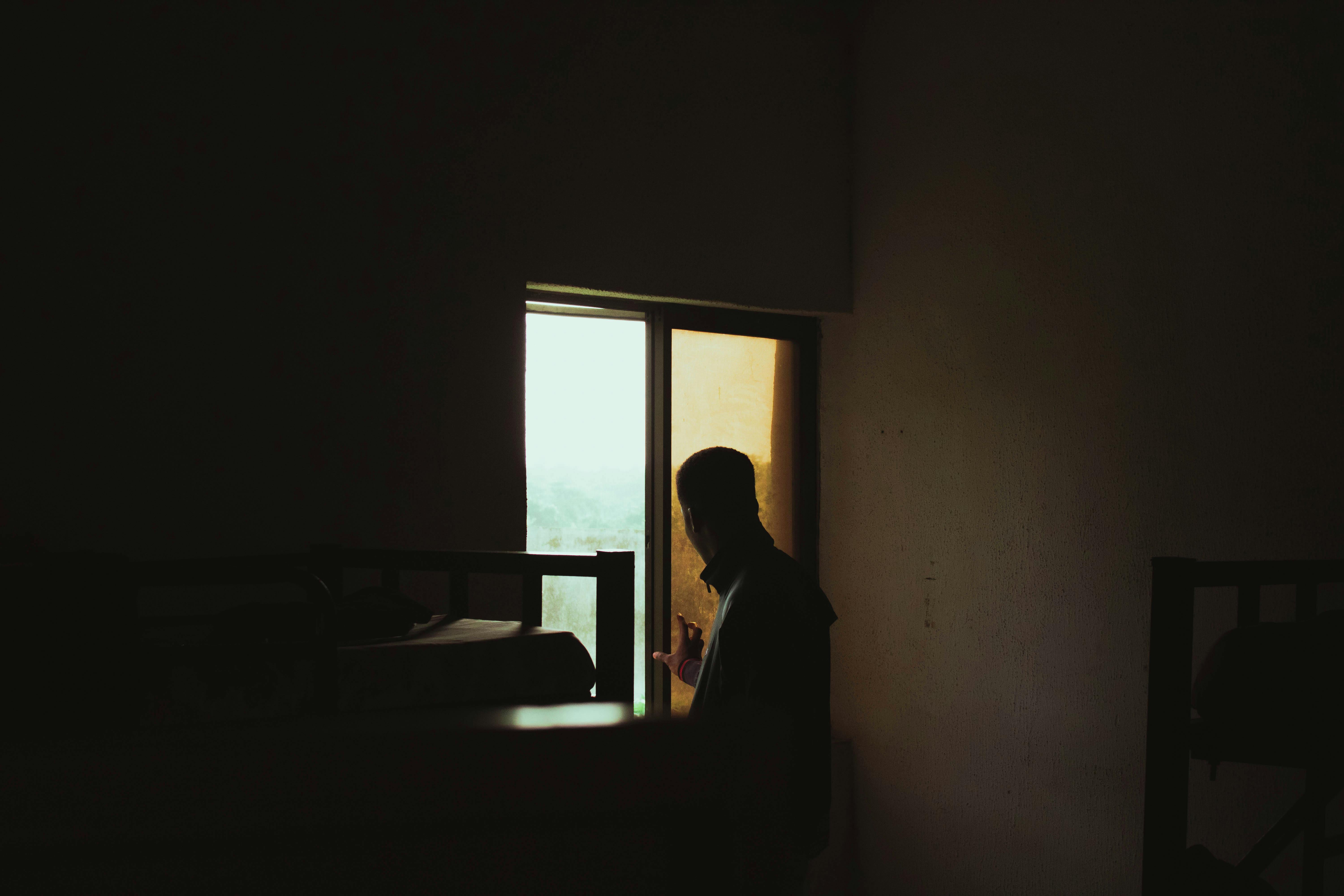Silhouette of a Man Standing by the Window in a Room · Free Stock Photo