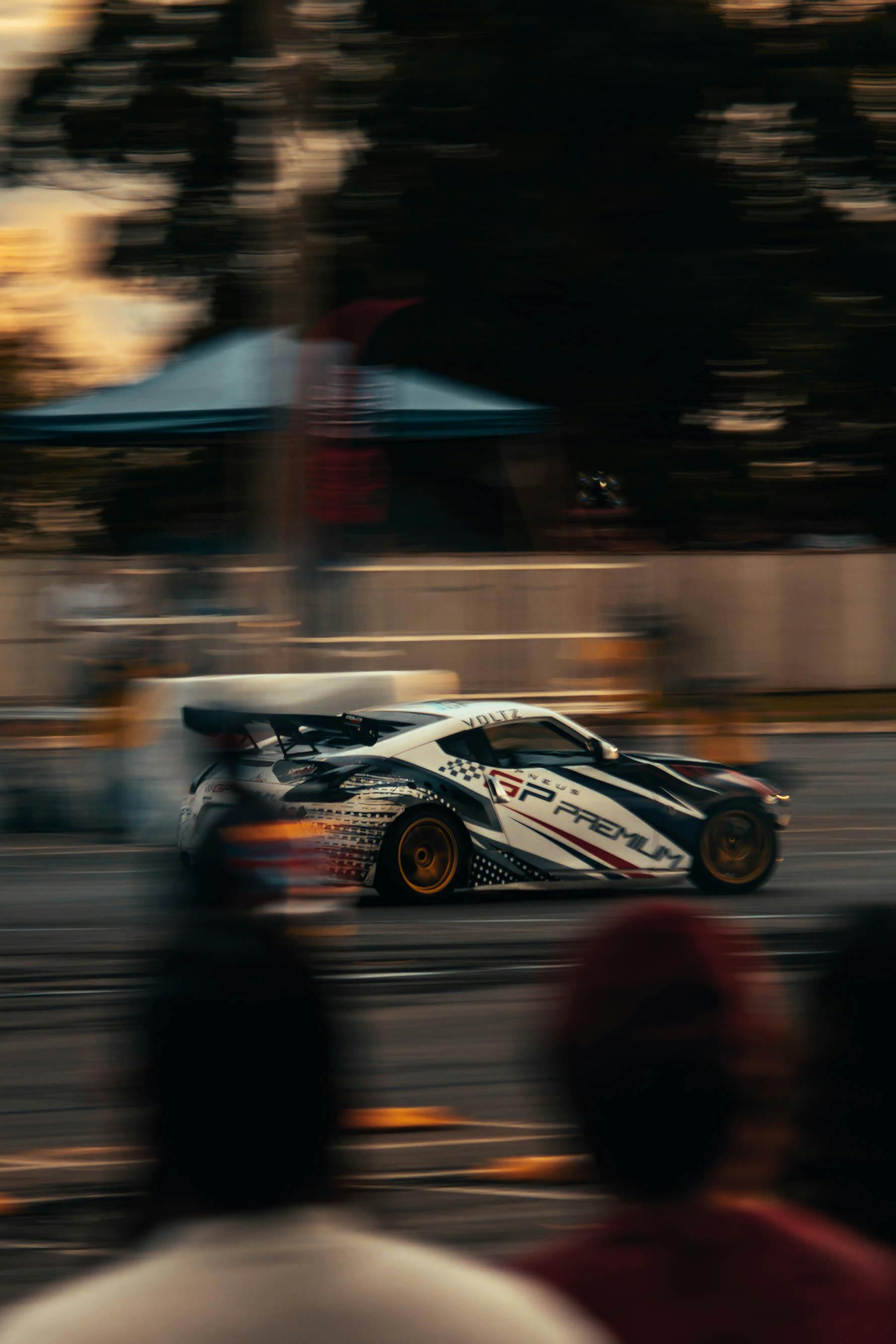 A car is racing down the street with blurry people · Free Stock Photo