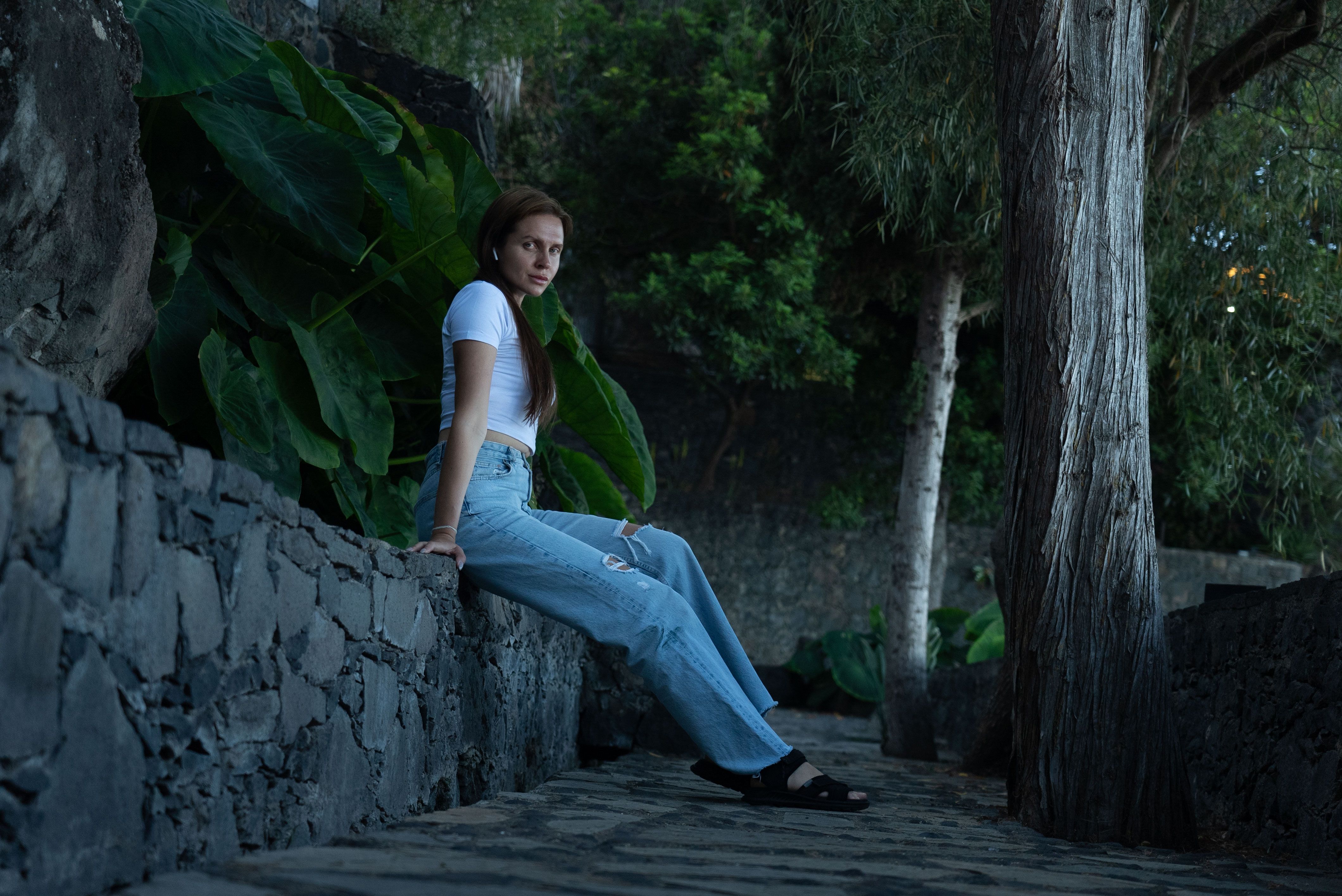 A Young Woman Sitting on a Stone Wall in the Garden · Free Stock Photo