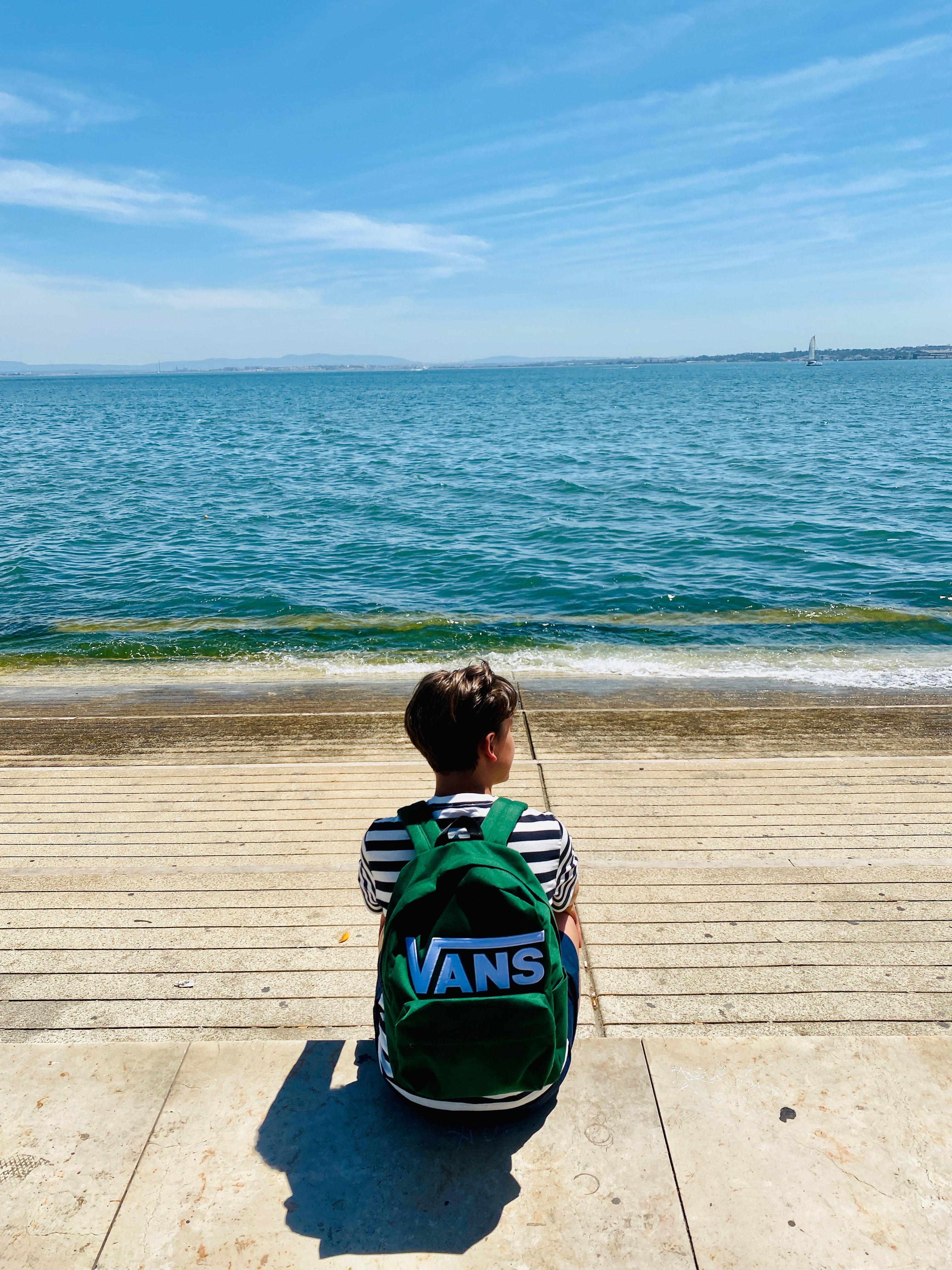 Person with Backpack Sitting on Sea Shore · Free Stock Photo