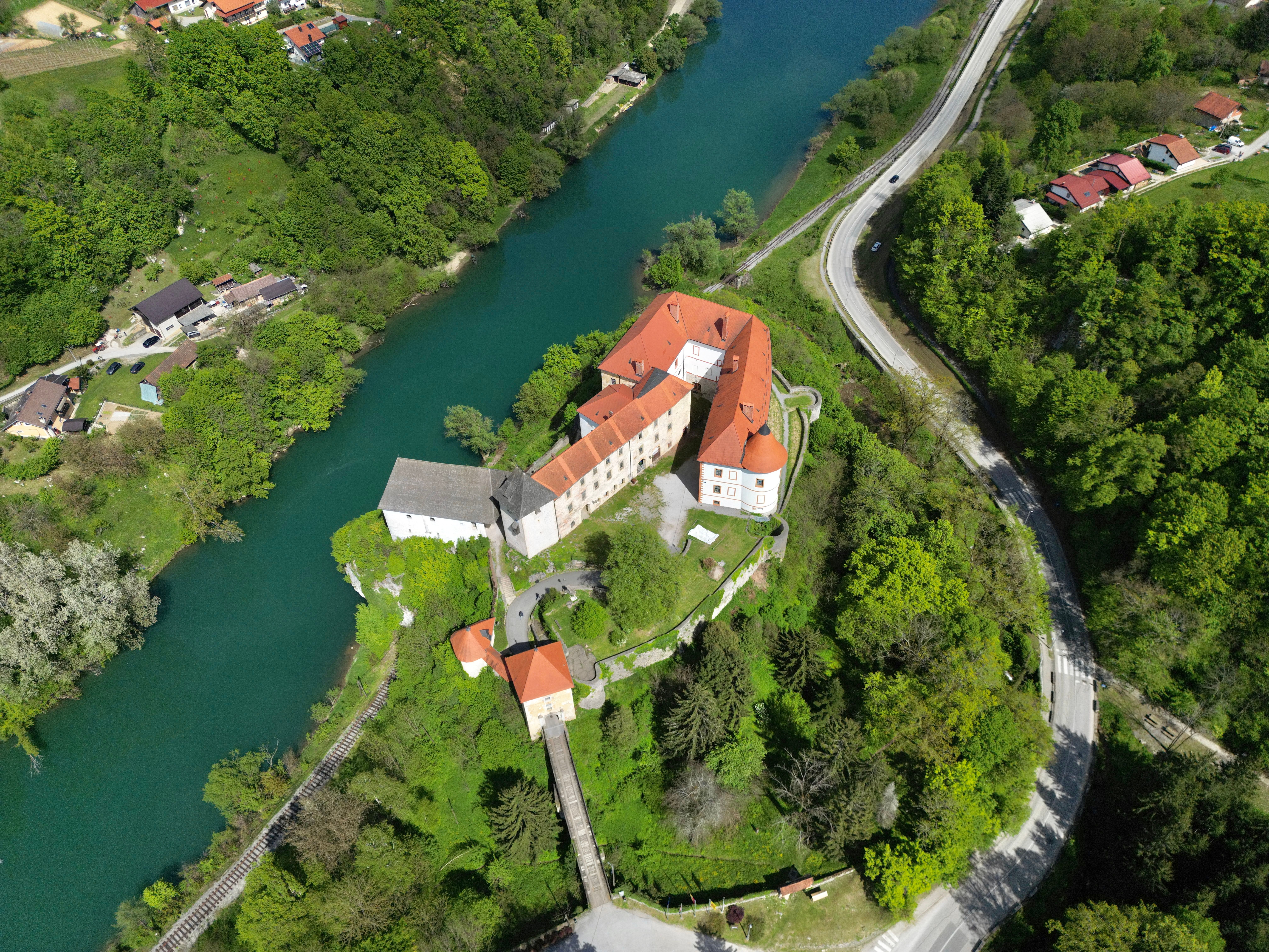 Aerial Footage of a Castle with a Red Roof by a River · Free Stock Photo
