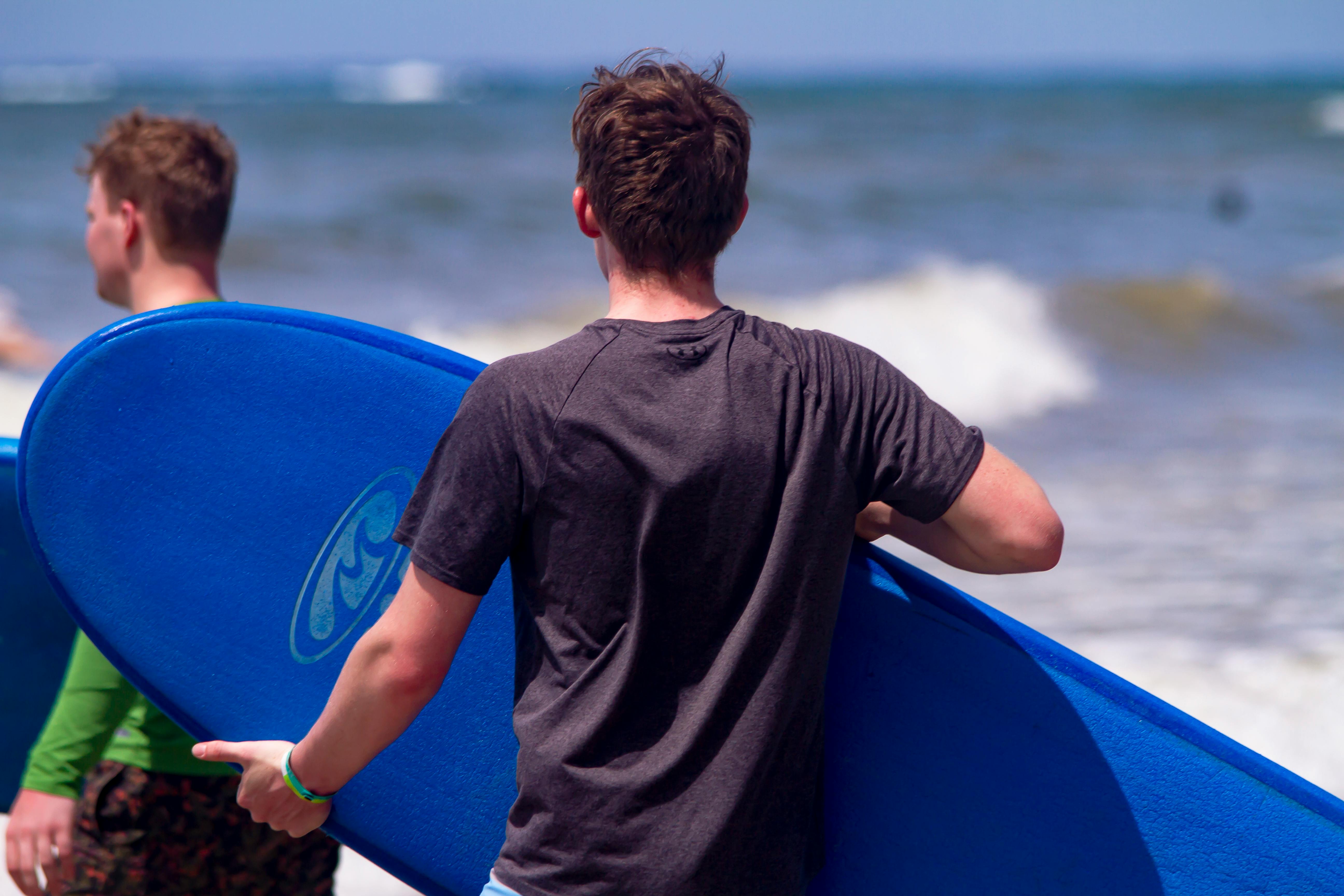 Two Surfers with a Surfboard · Free Stock Photo