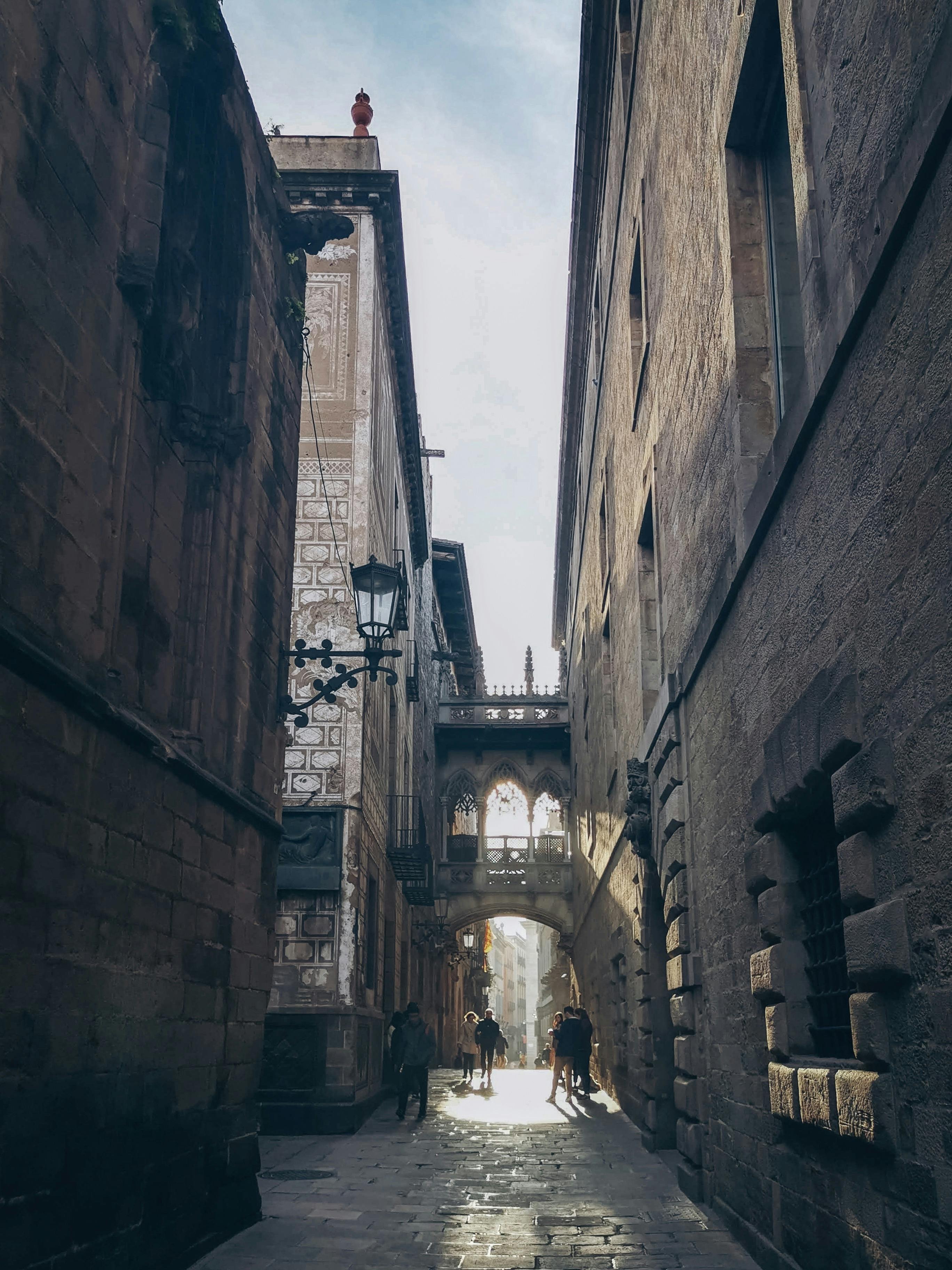 People Walking in Between Stone Walled Buildings Along A Narrow ...