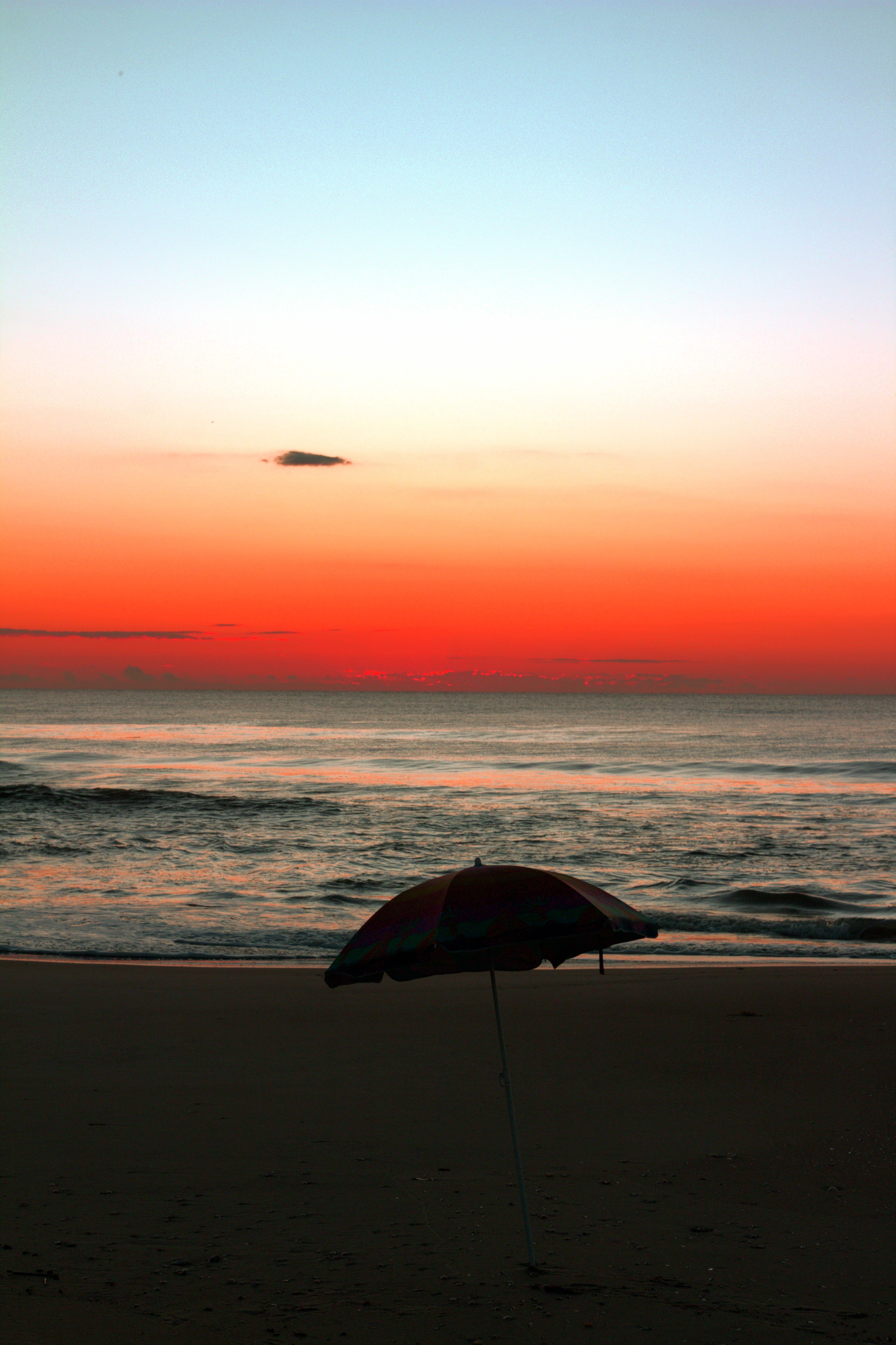 Silhouetted Umbrella on the Beach at Sunset · Free Stock Photo